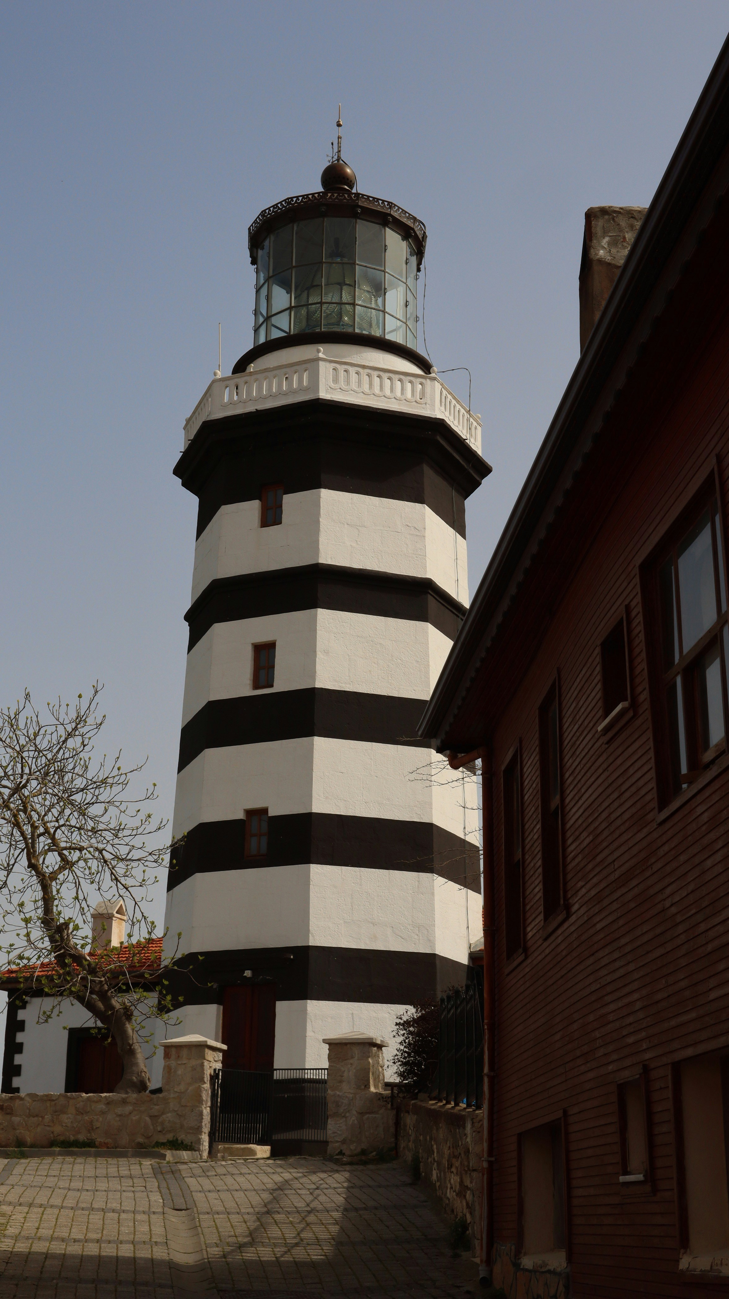 Stripe-Tower Beacon: A Lighthouse Framed by Brick and Sky