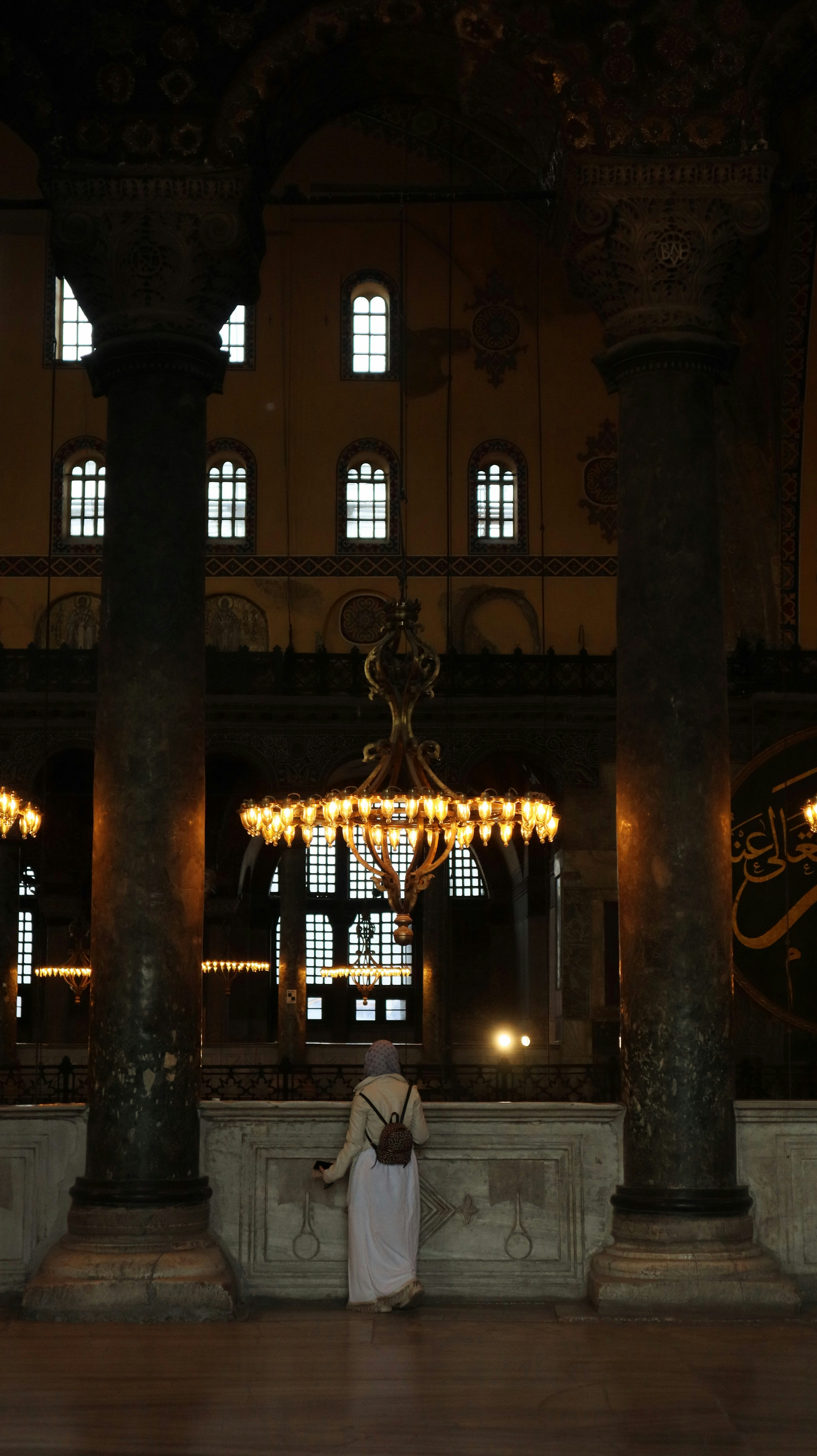 Pilgrim Beneath the Lantern Crown in a Mosque Hall