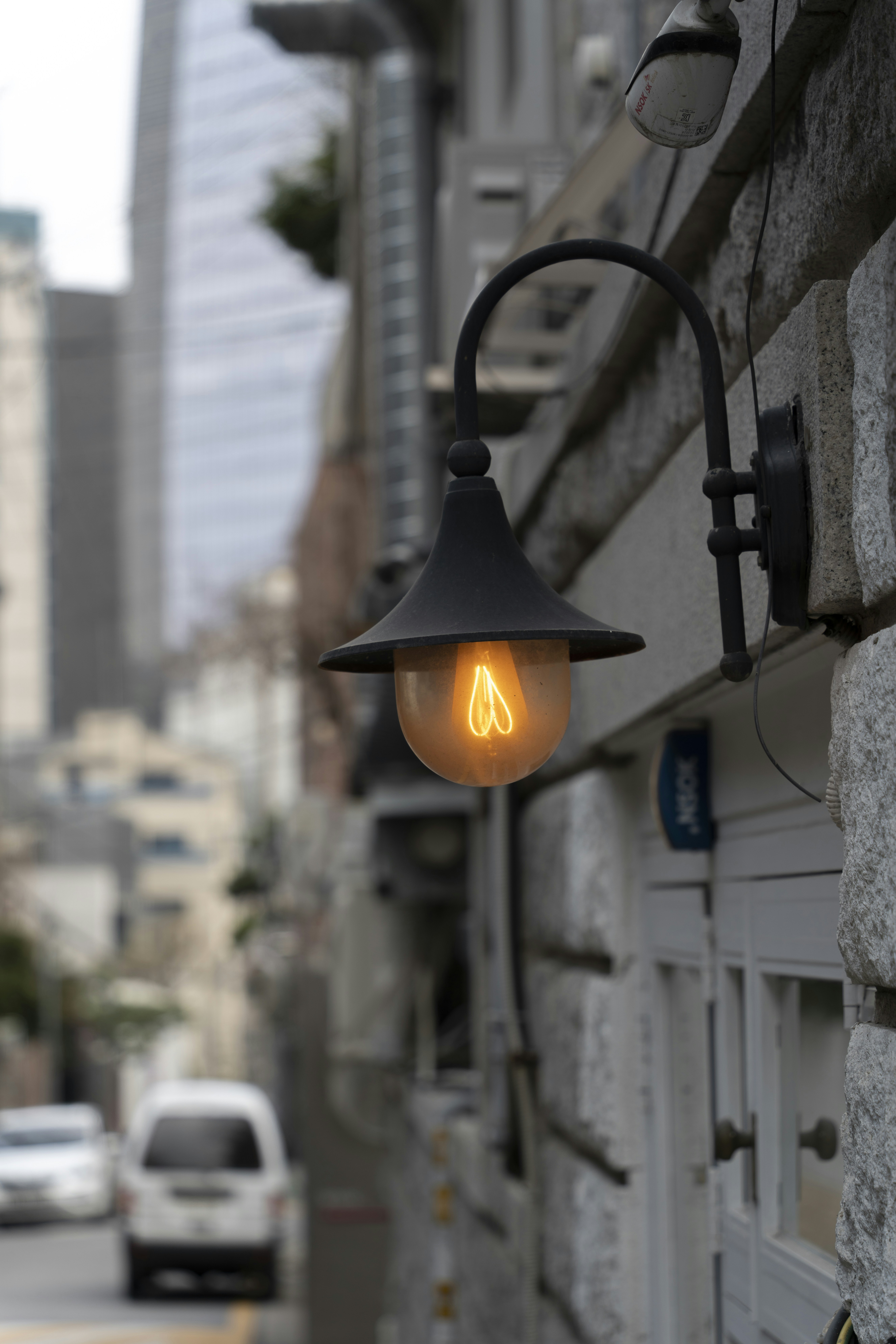 Urban Lantern Glow: Edison Light on Rough Stone Facade
