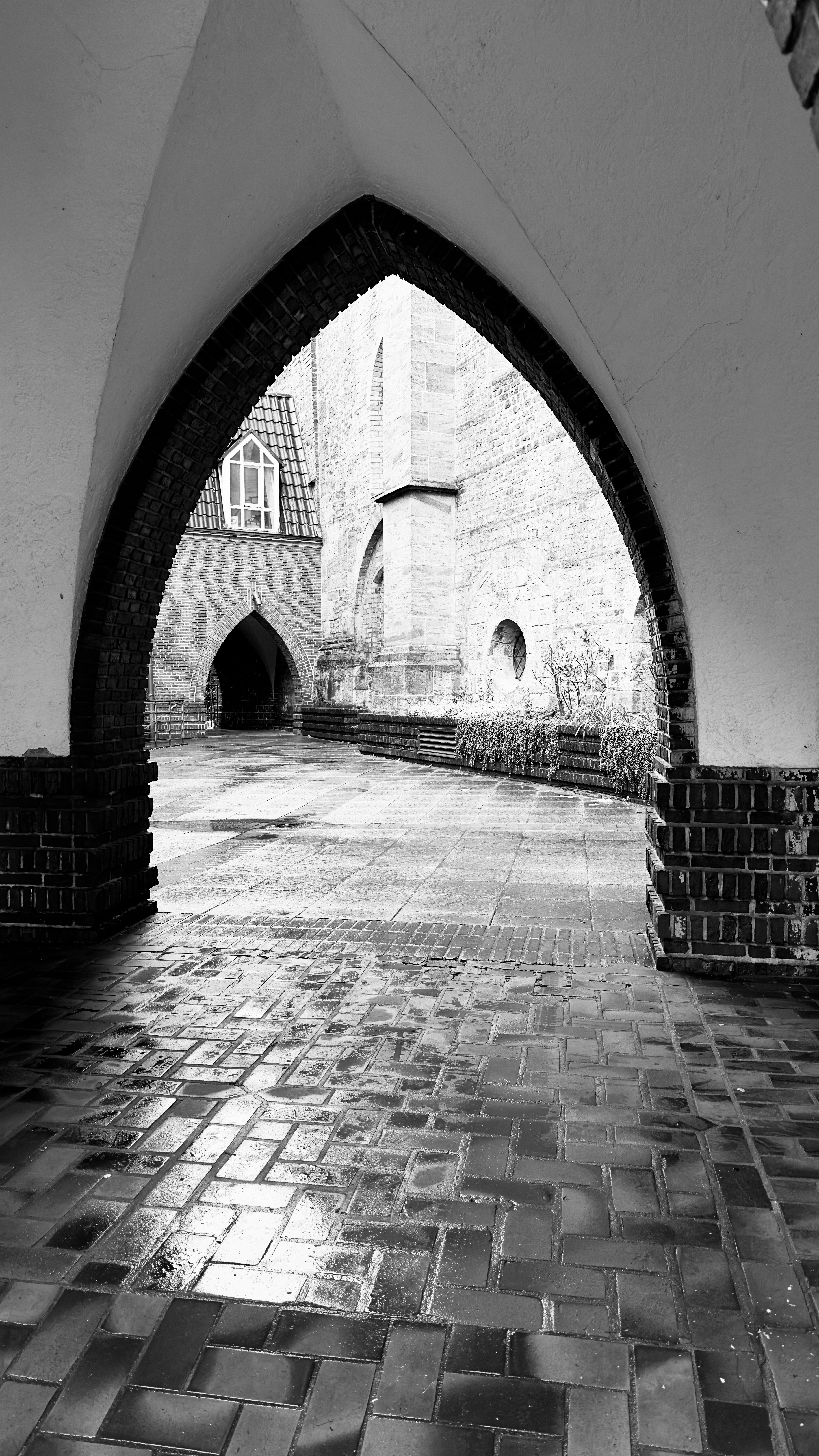 Through the Dark Arch: A Monochrome Courtyard Framed by Brick Arches