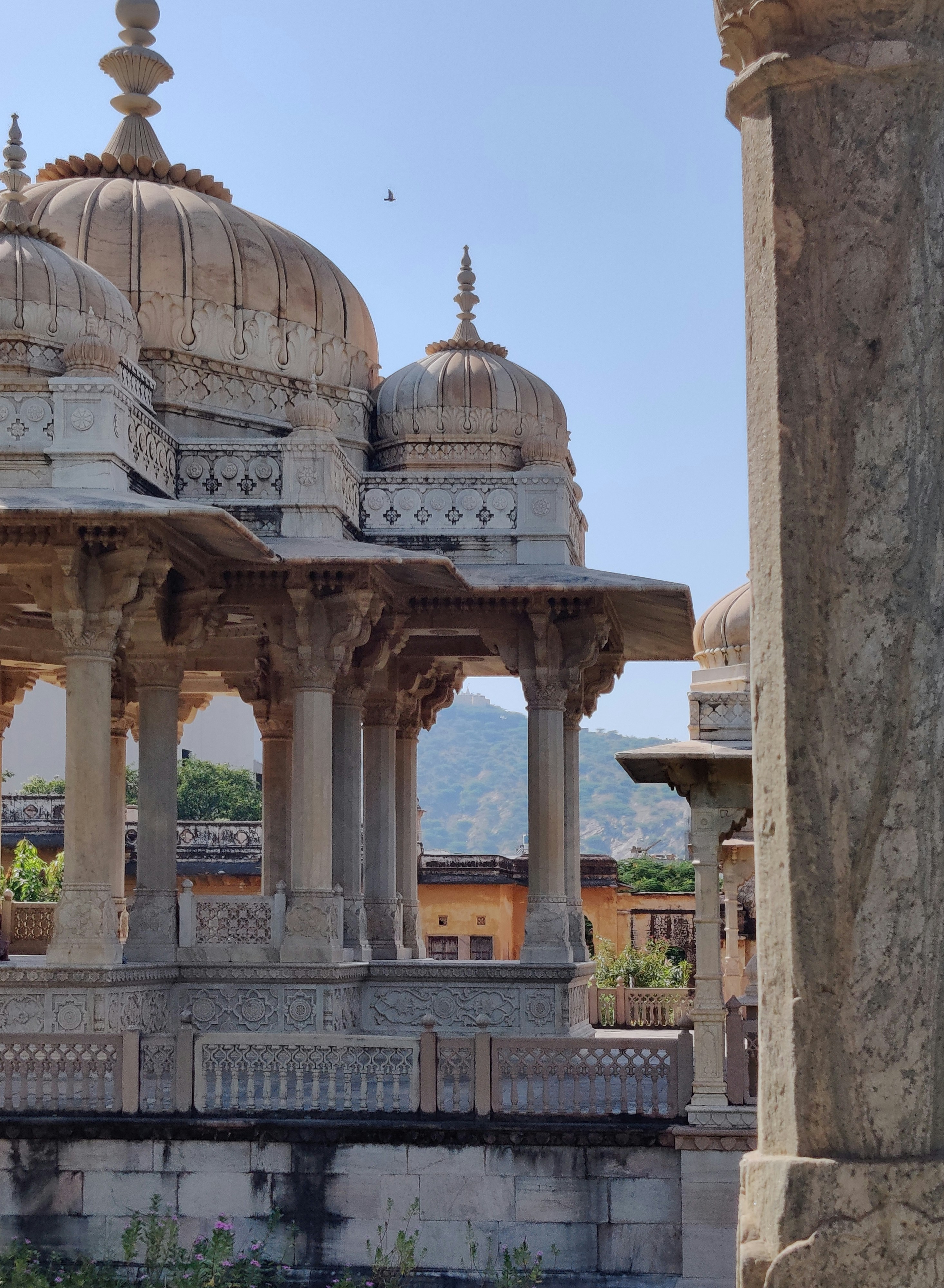 Intricately carved domes and columns of a historic structure against a clear blue sky.