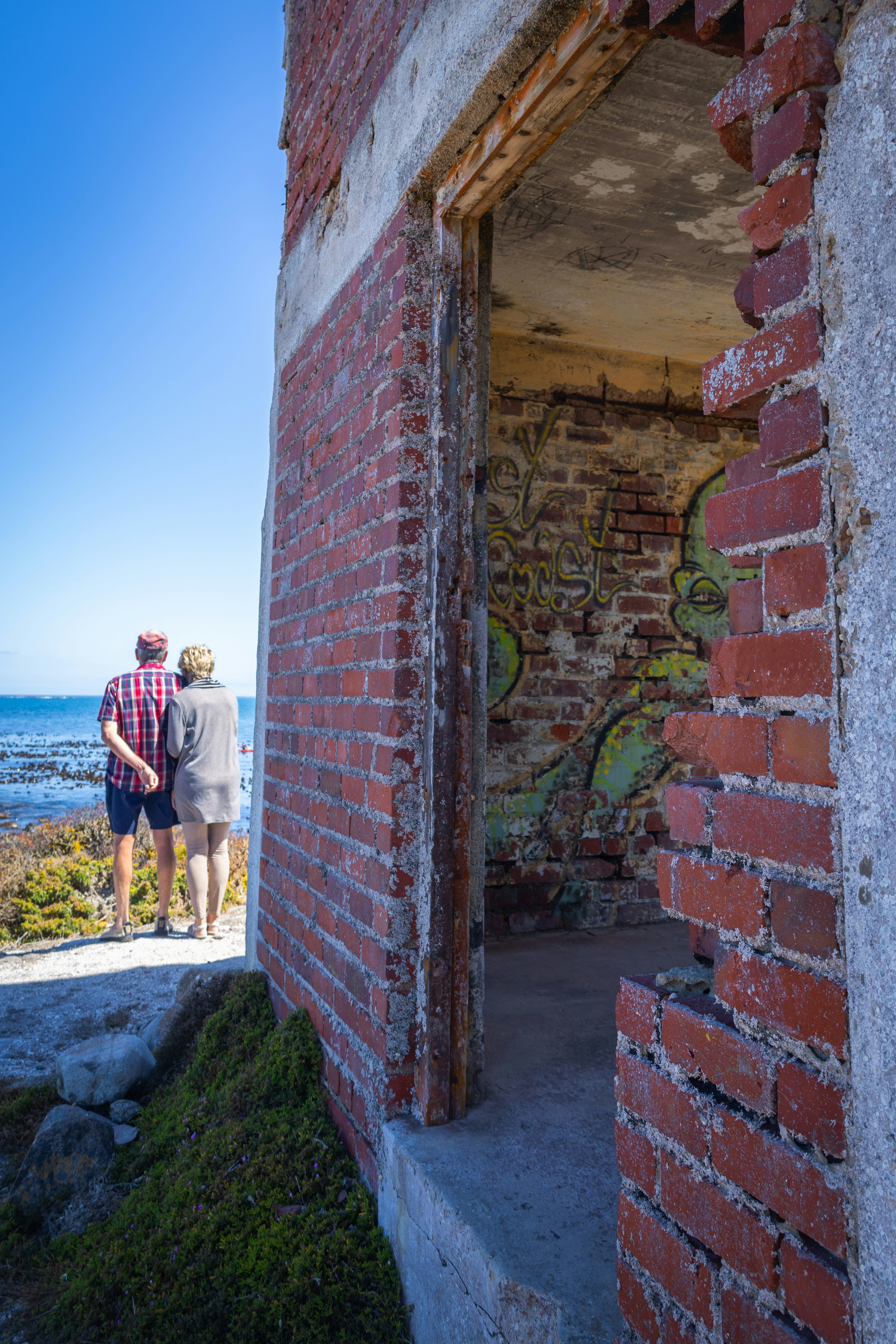 Sea-kissed threshold: a couple by a weathered brick ruin