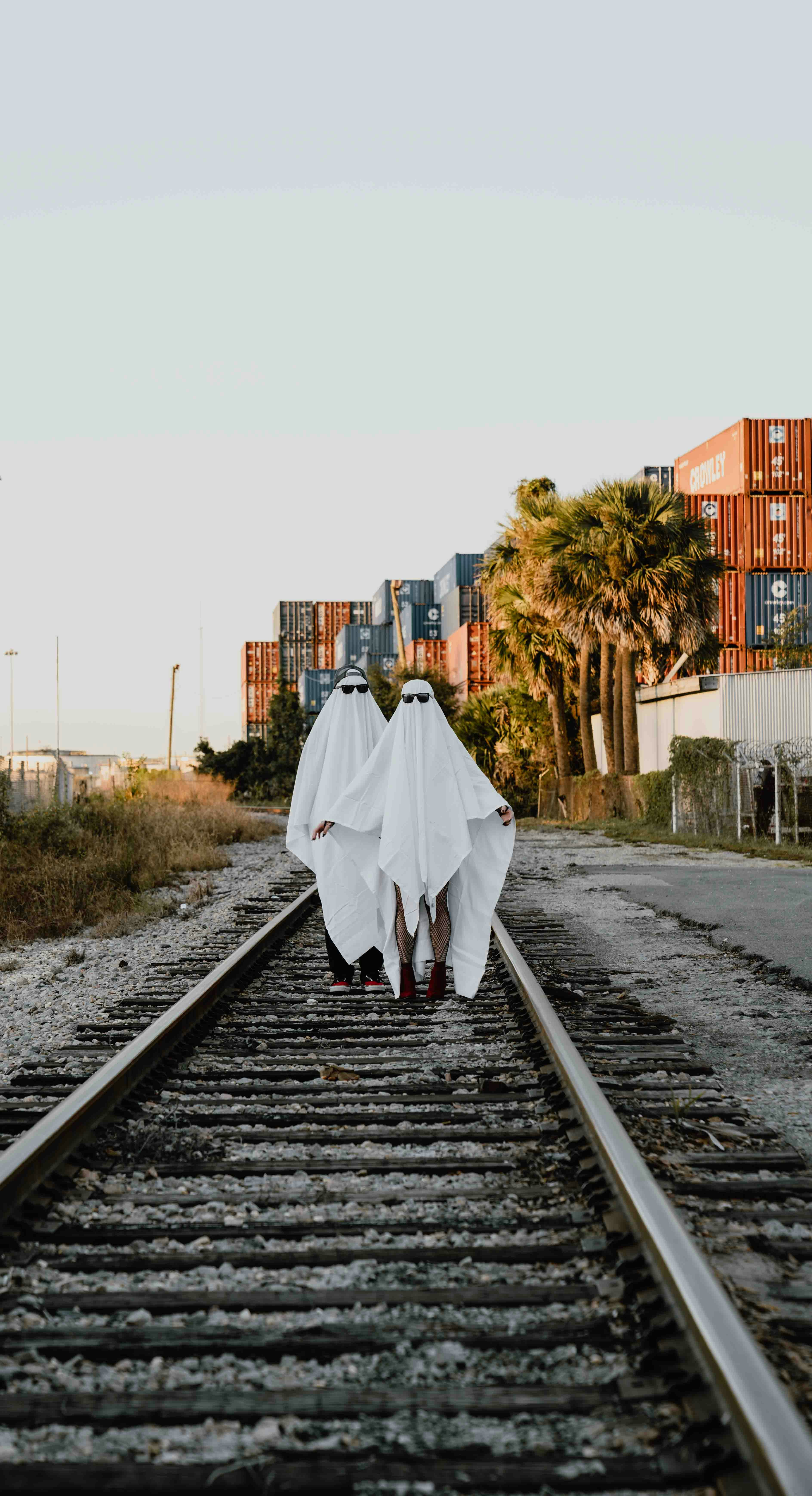 Three White Cloaks on the Rails: Ghostly Parade Through a Container Yard at Sunset