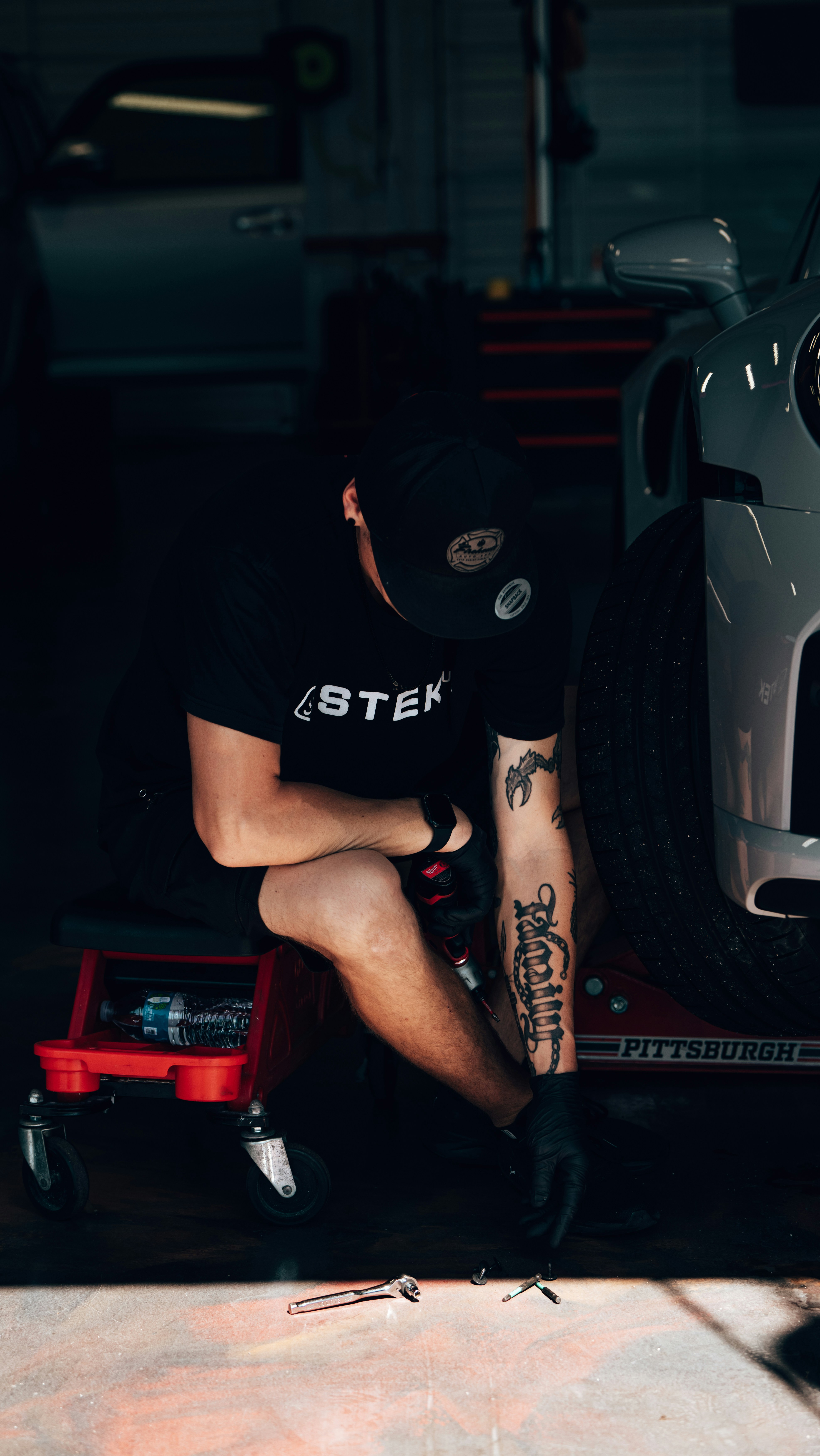A Mechanic in Shadow: Hands at the Wheel of a Car on a Lift
