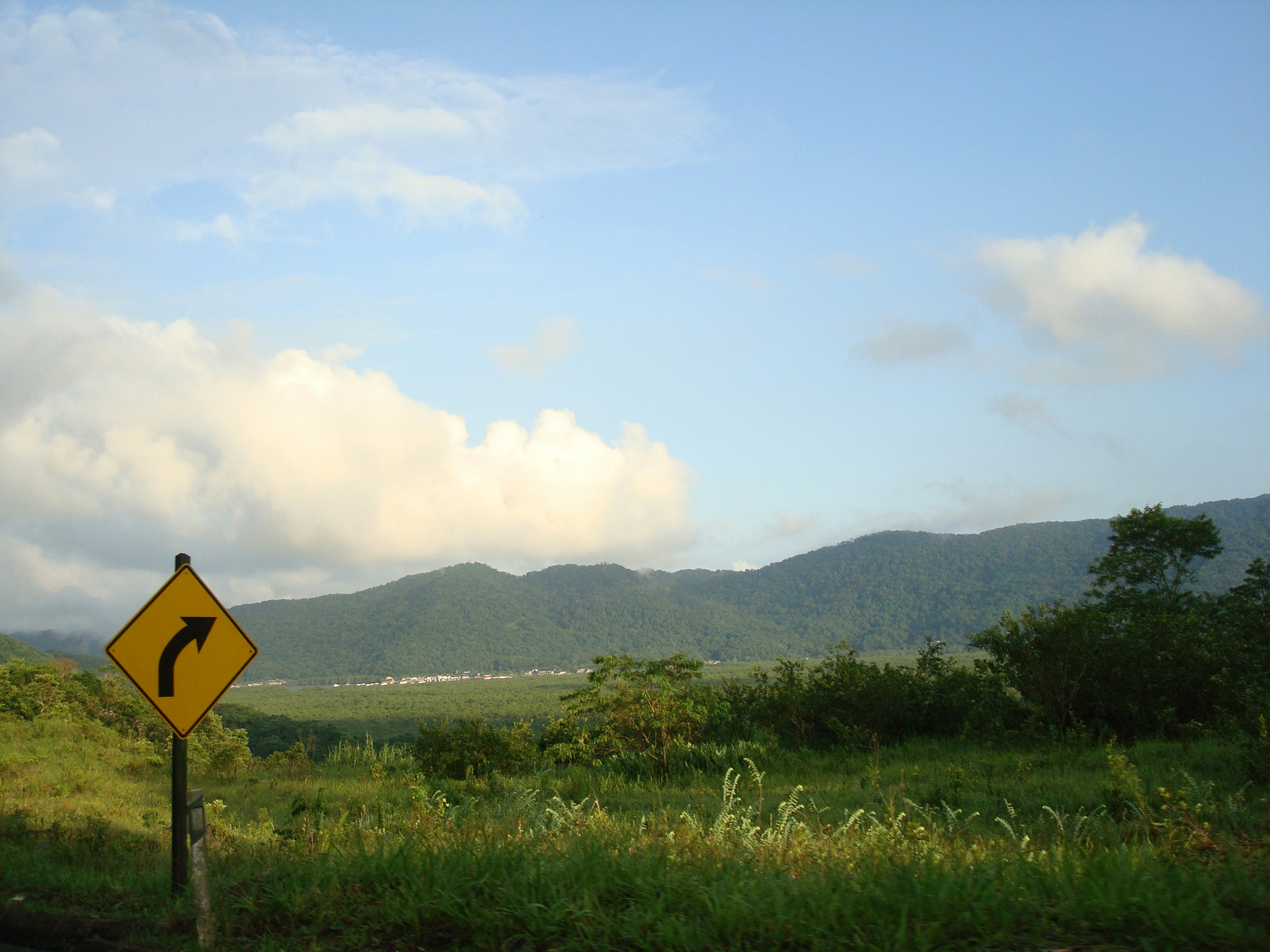 Rural Bend: A Road Sign Framing a Quiet Valley Between Hills