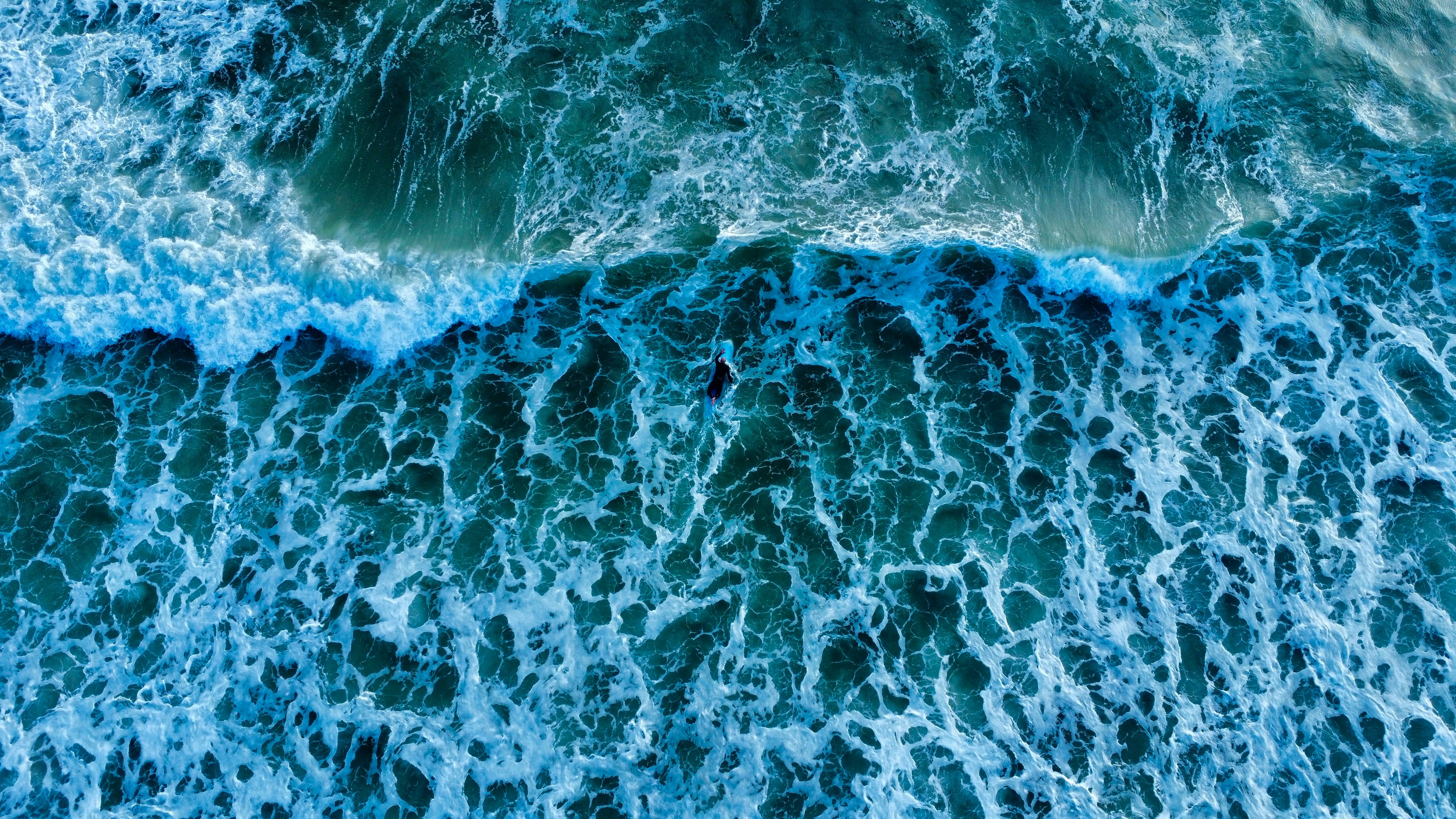 Waves crashing in rhythmic patterns viewed from above, showcasing the ocean's dynamic textures.