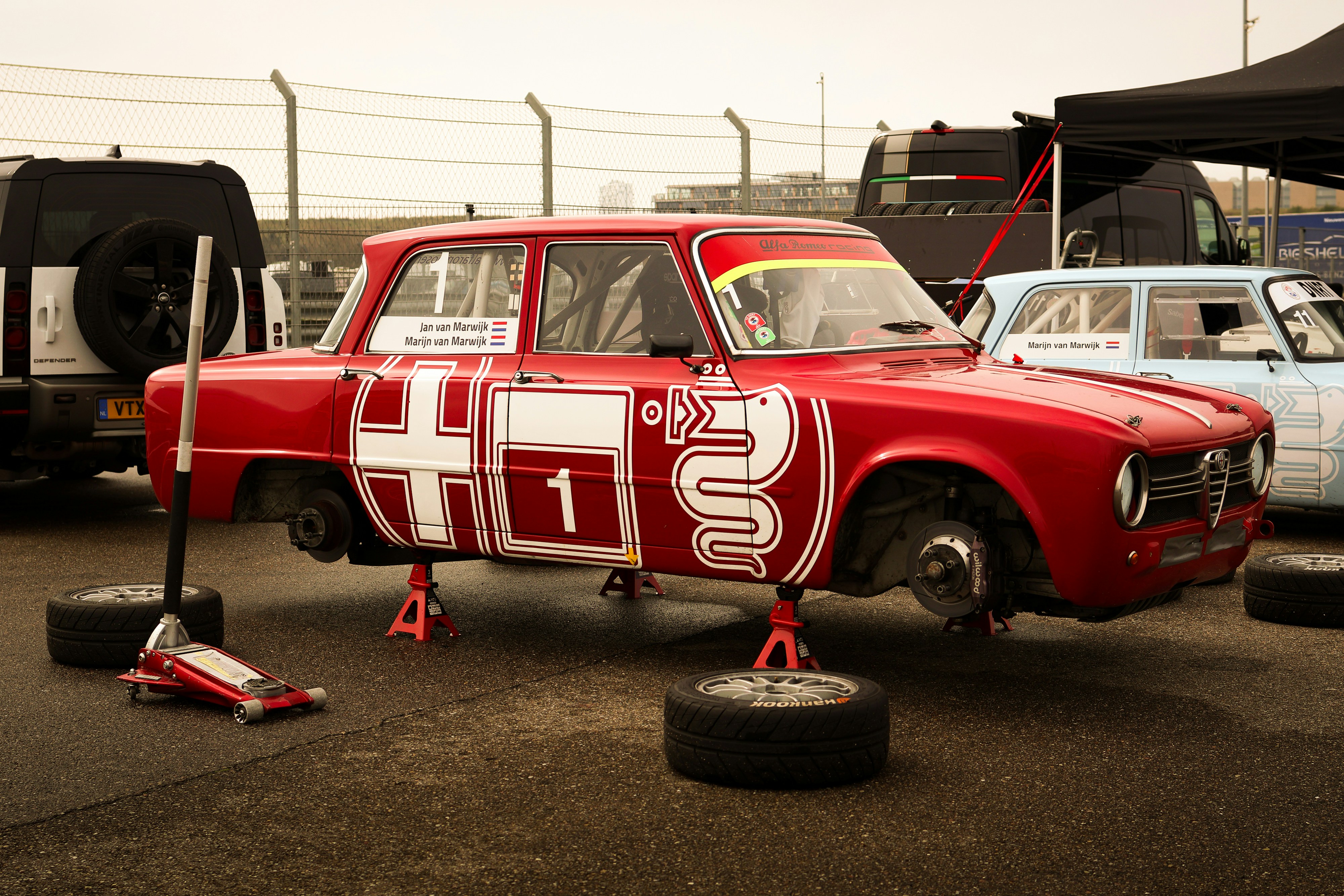 Red Racer Relic at the Pit: A Vintage Touring Car with Bold White Livery