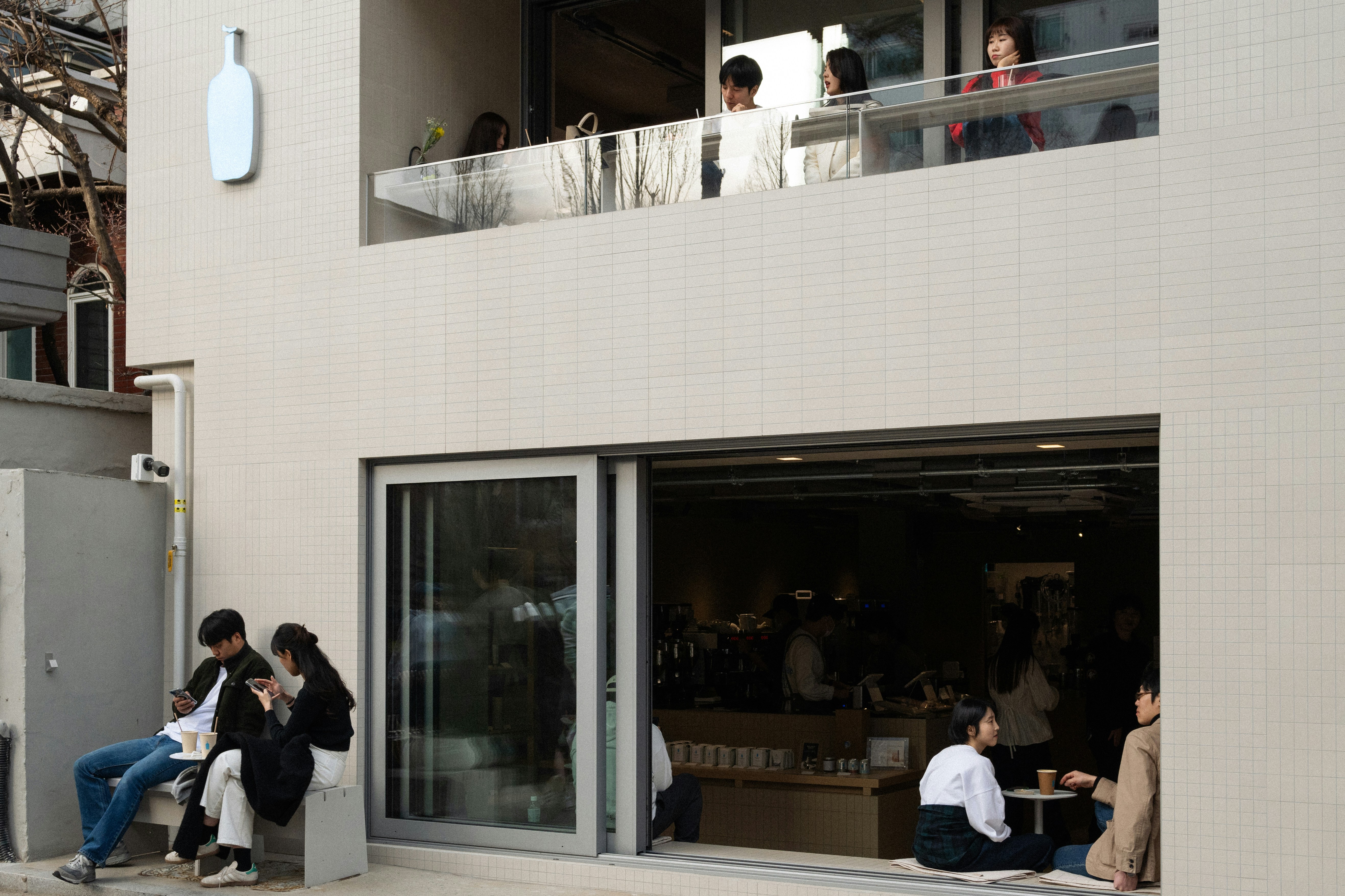 A group of people sitting outside of a building photo – Free Street ...