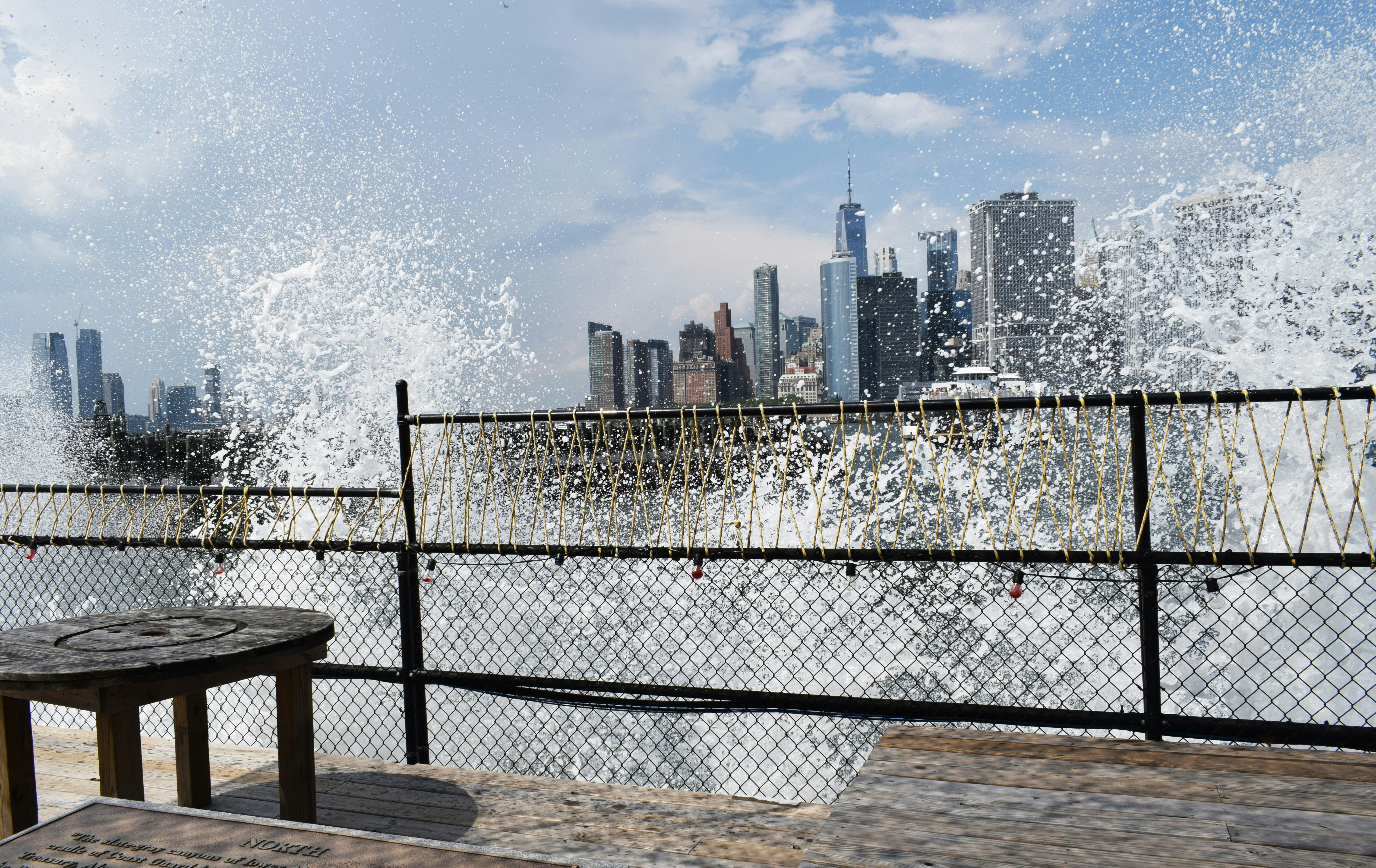 Hydro-Glint at the Pier: Spray Arches Against a Skyscraper Backdrop
