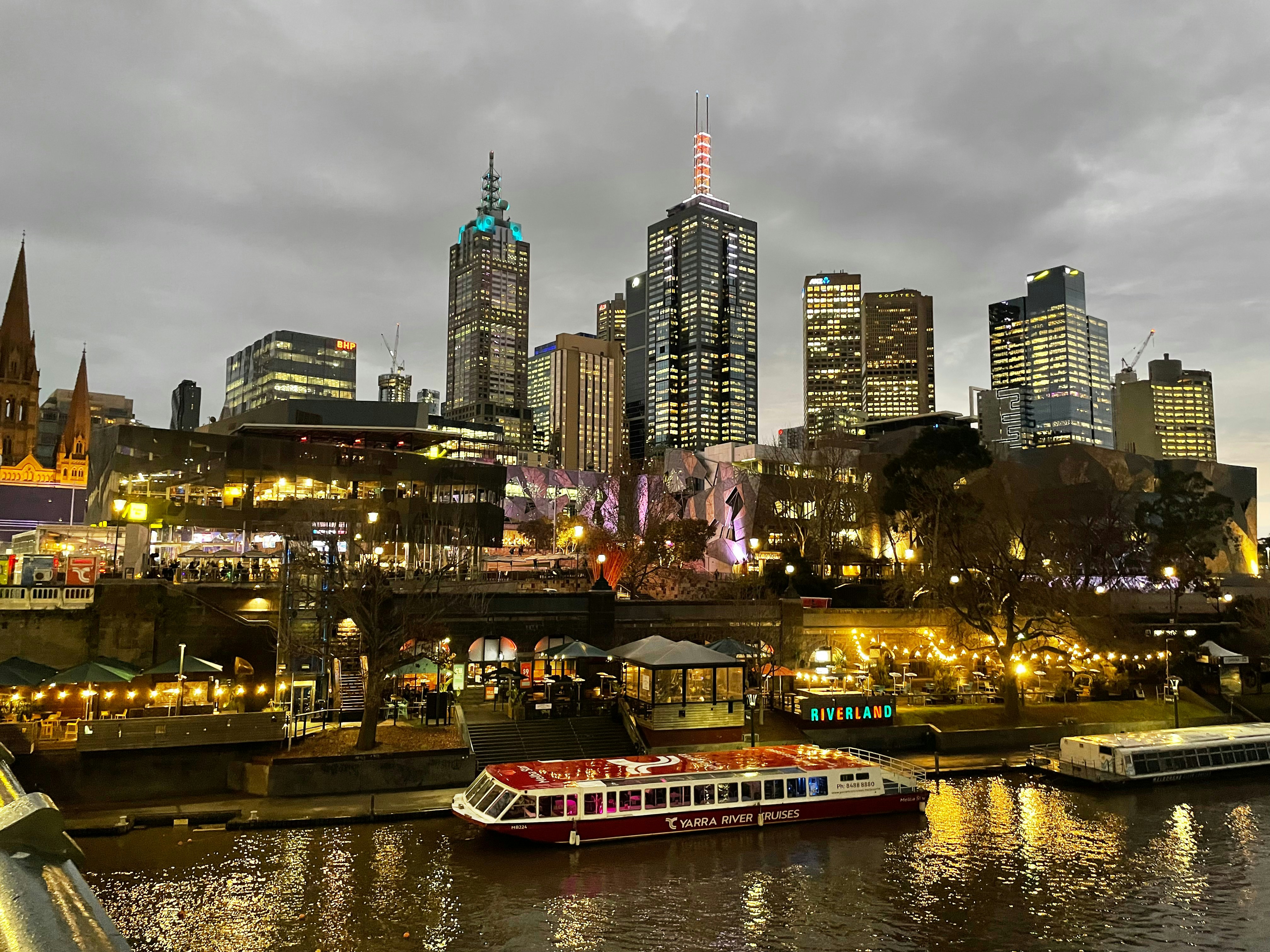 A boat floating on top of a river next to tall buildings photo – Free ...