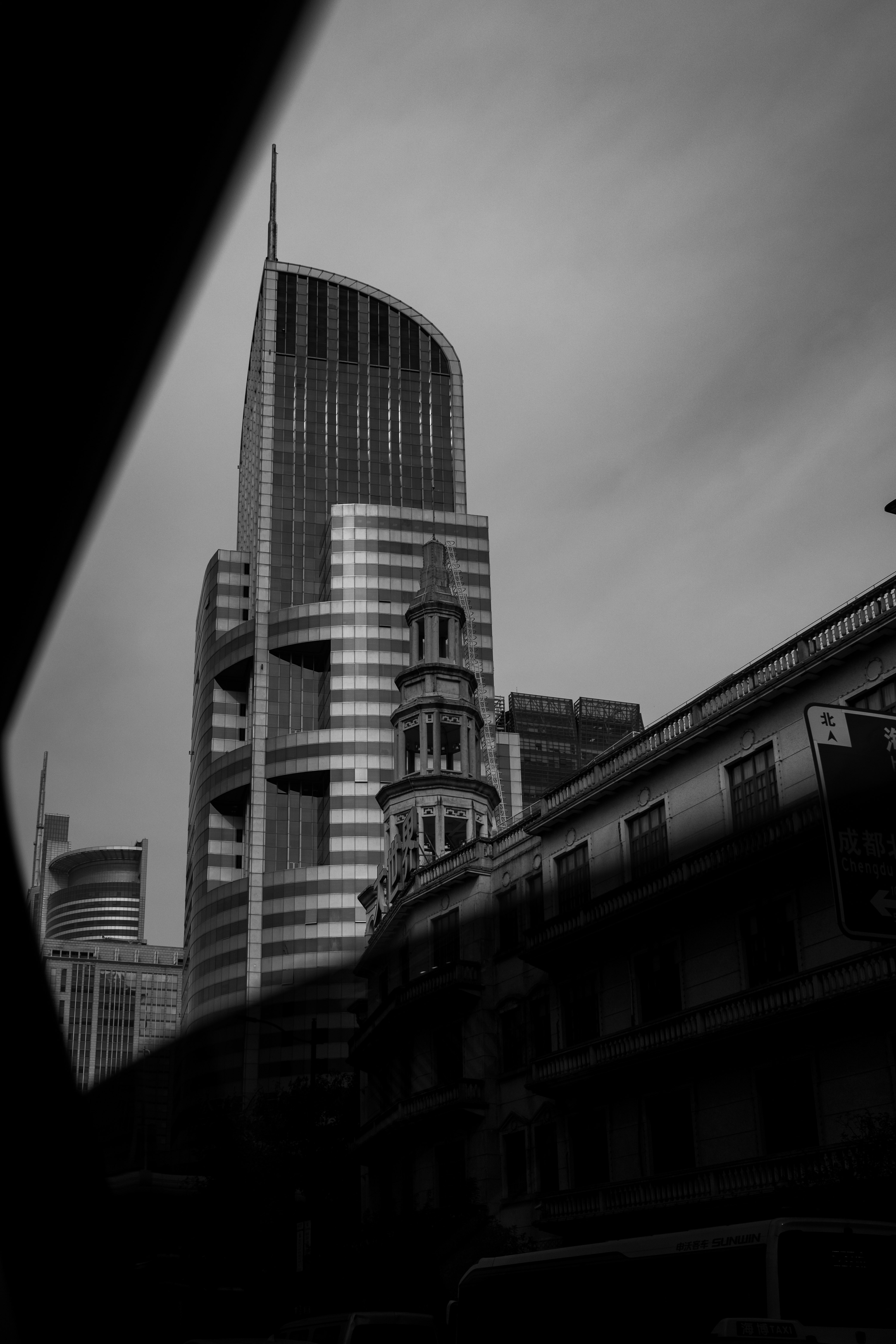 Shadowed Arc: The Glass Tower Against a Historic Facade
