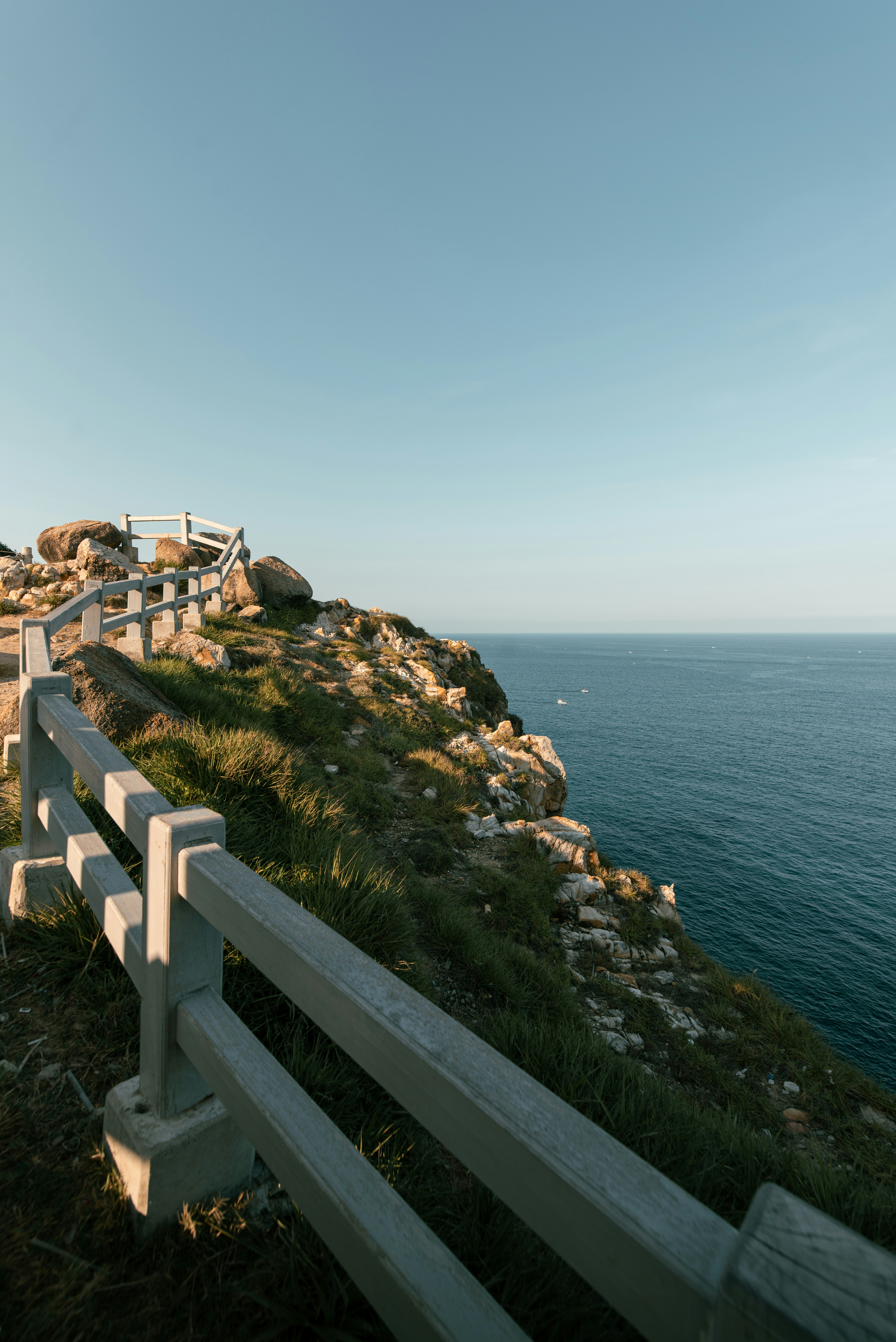A wooden bench sitting on the side of a cliff next to the ocean photo ...