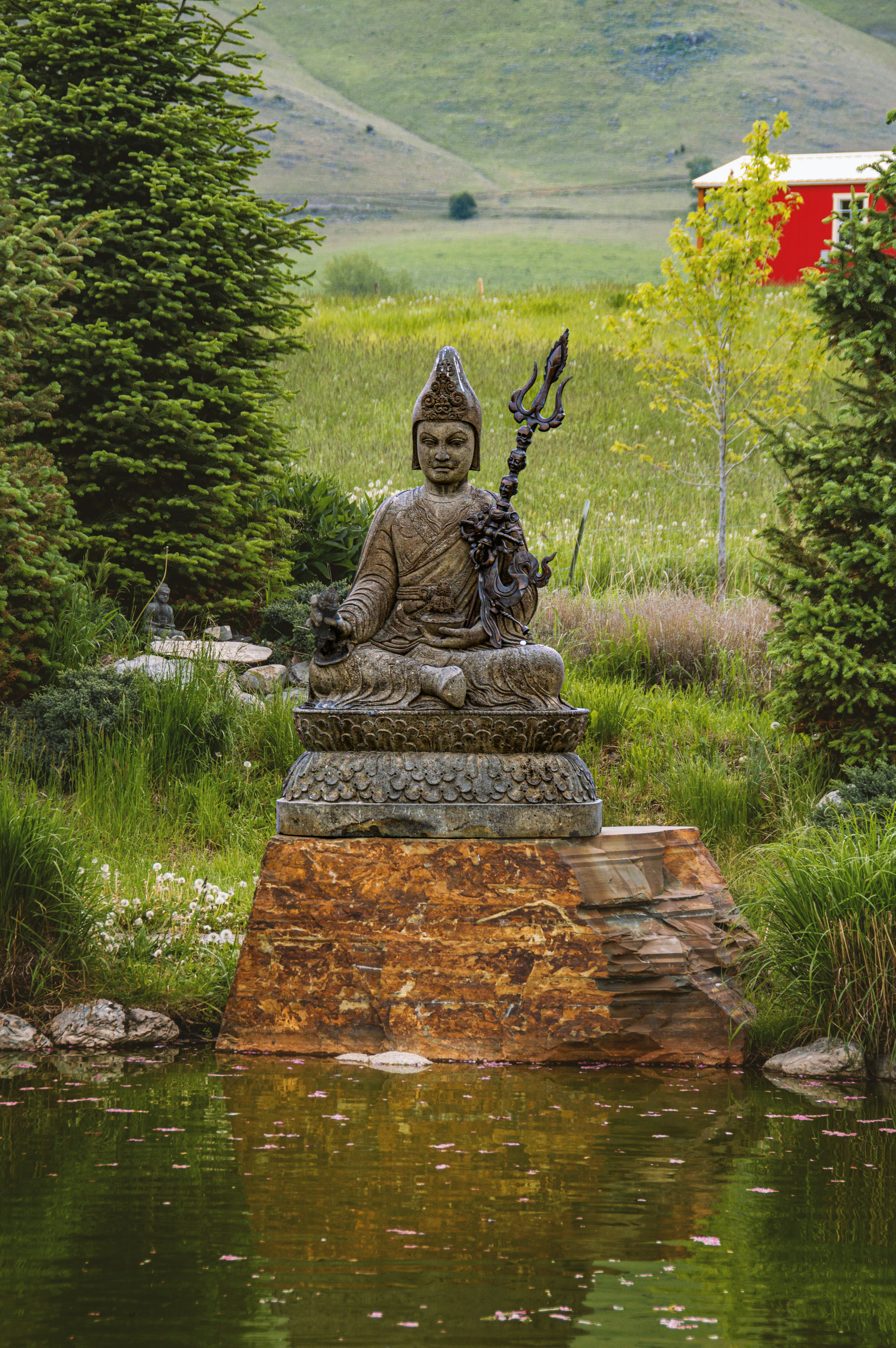 Verdant Sanctuary: Seated Buddha on a Stone Pedestal Over a Reflective Pond
