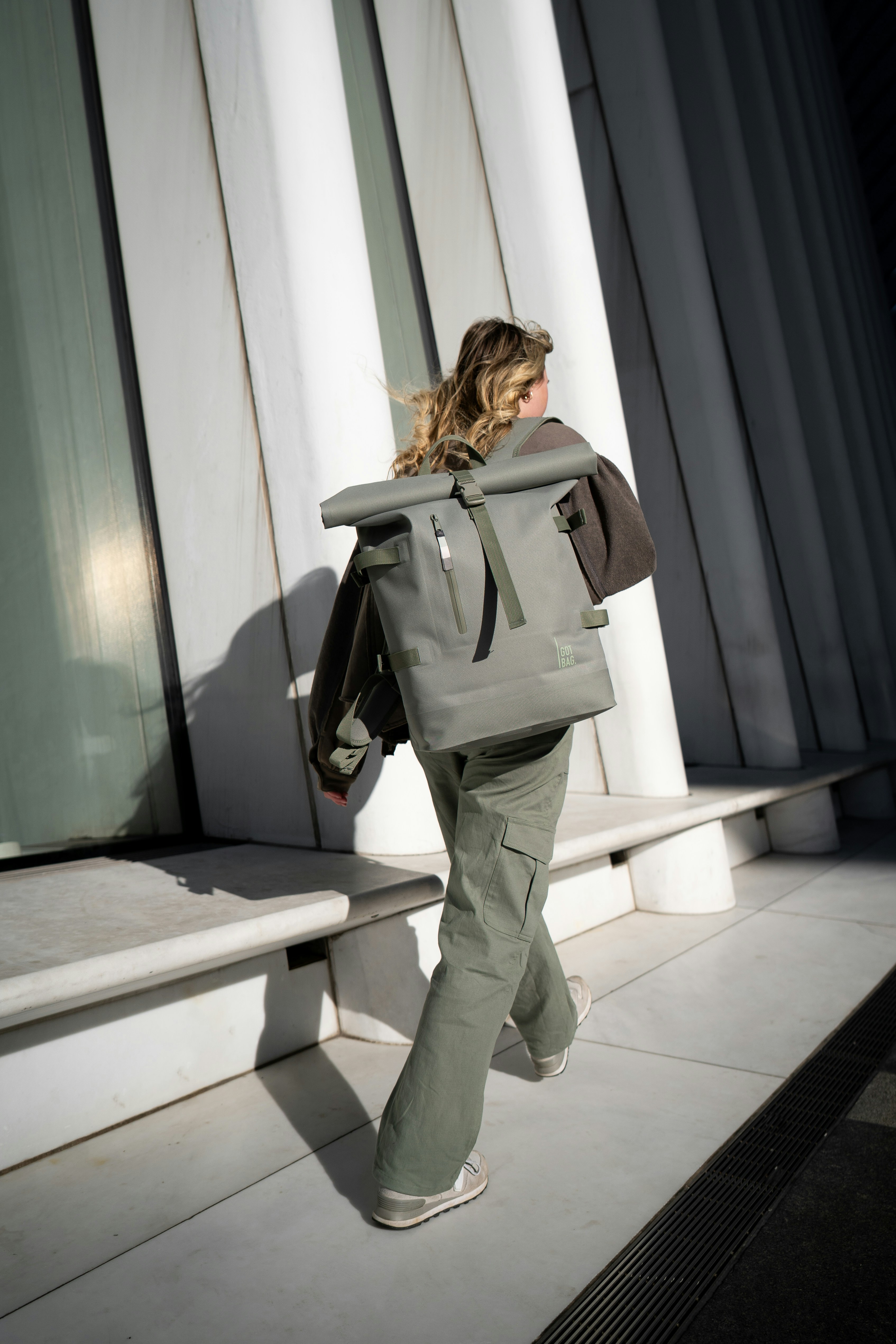 A woman walking down a sidewalk with a backpack on her back photo ...