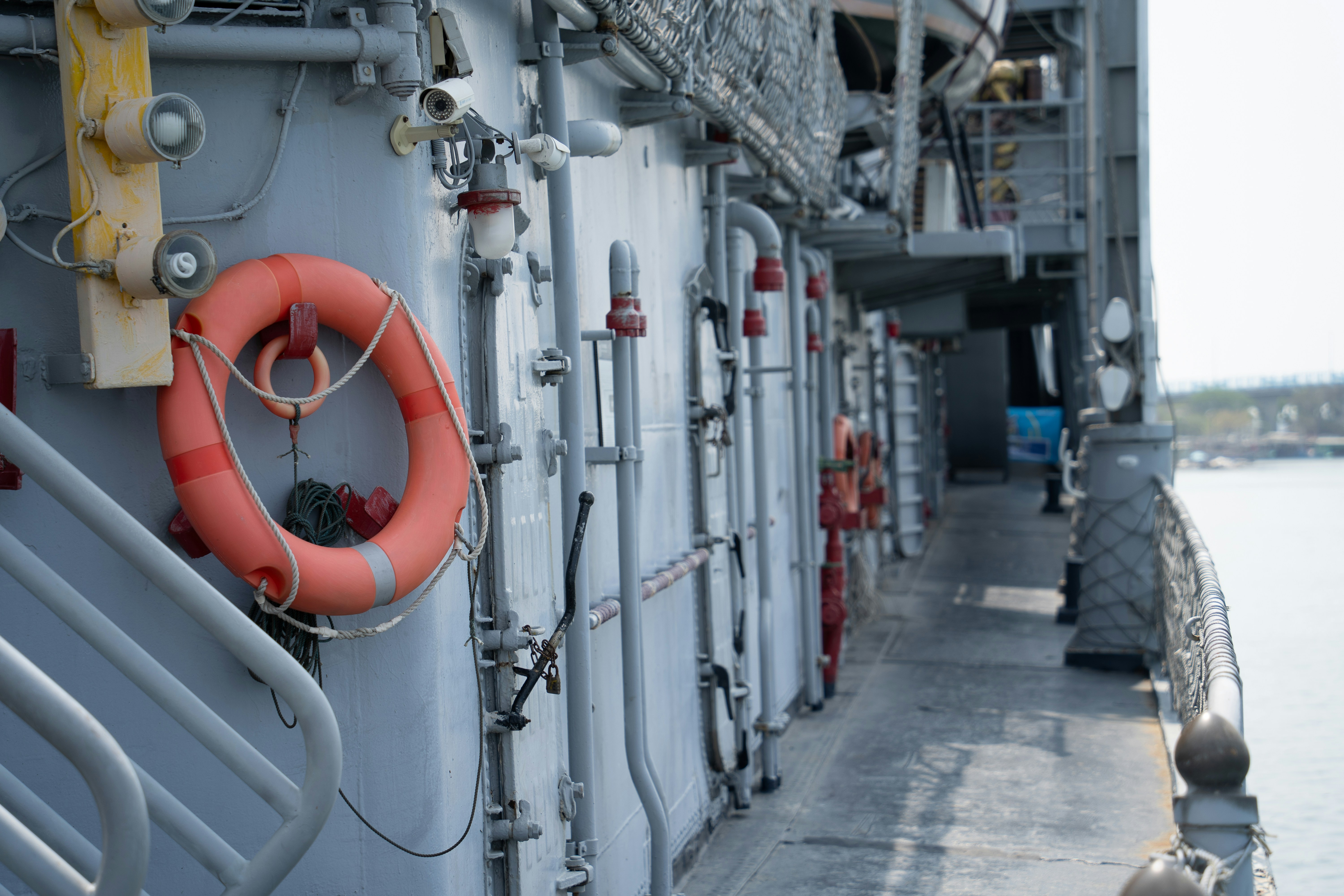 Lifebuoy mounted on a ship's railing alongside a series of safety equipment. The scene highlights maritime safety features on a vessel.