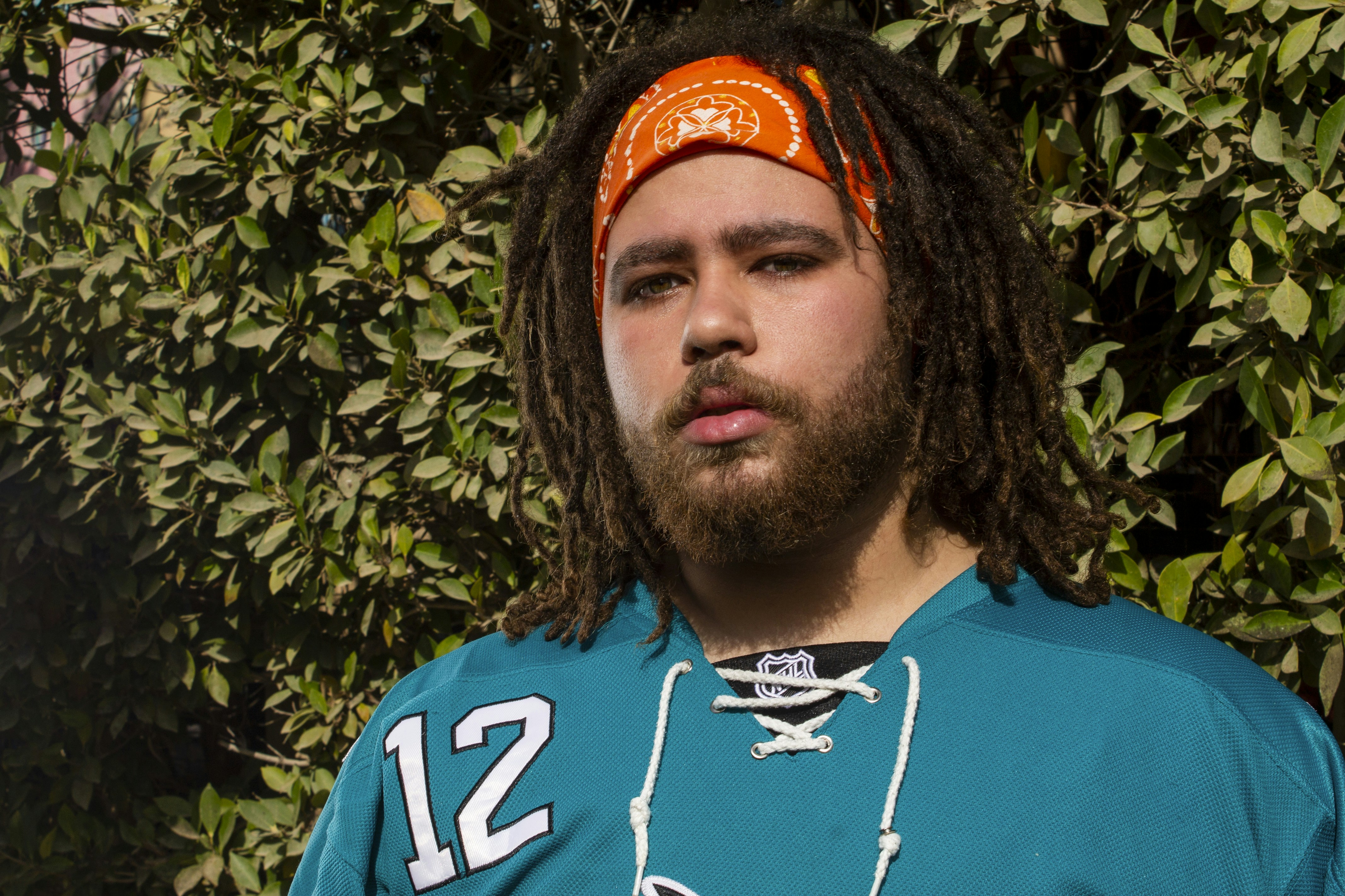 A man with dreadlocks standing in front of a bush photo – Free Portrait ...