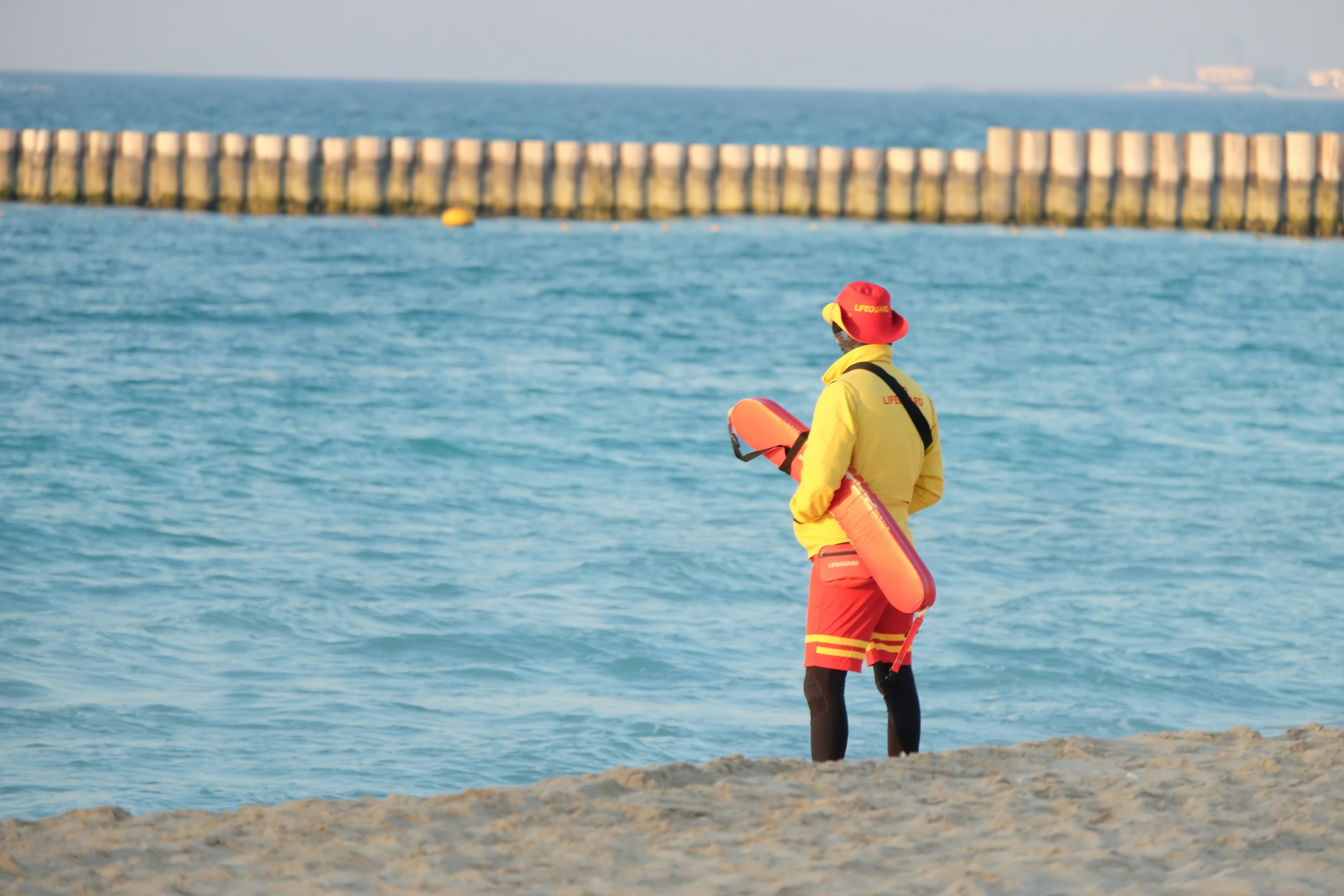 Lifeguard in Bright Gear Stands Watch by the Sea