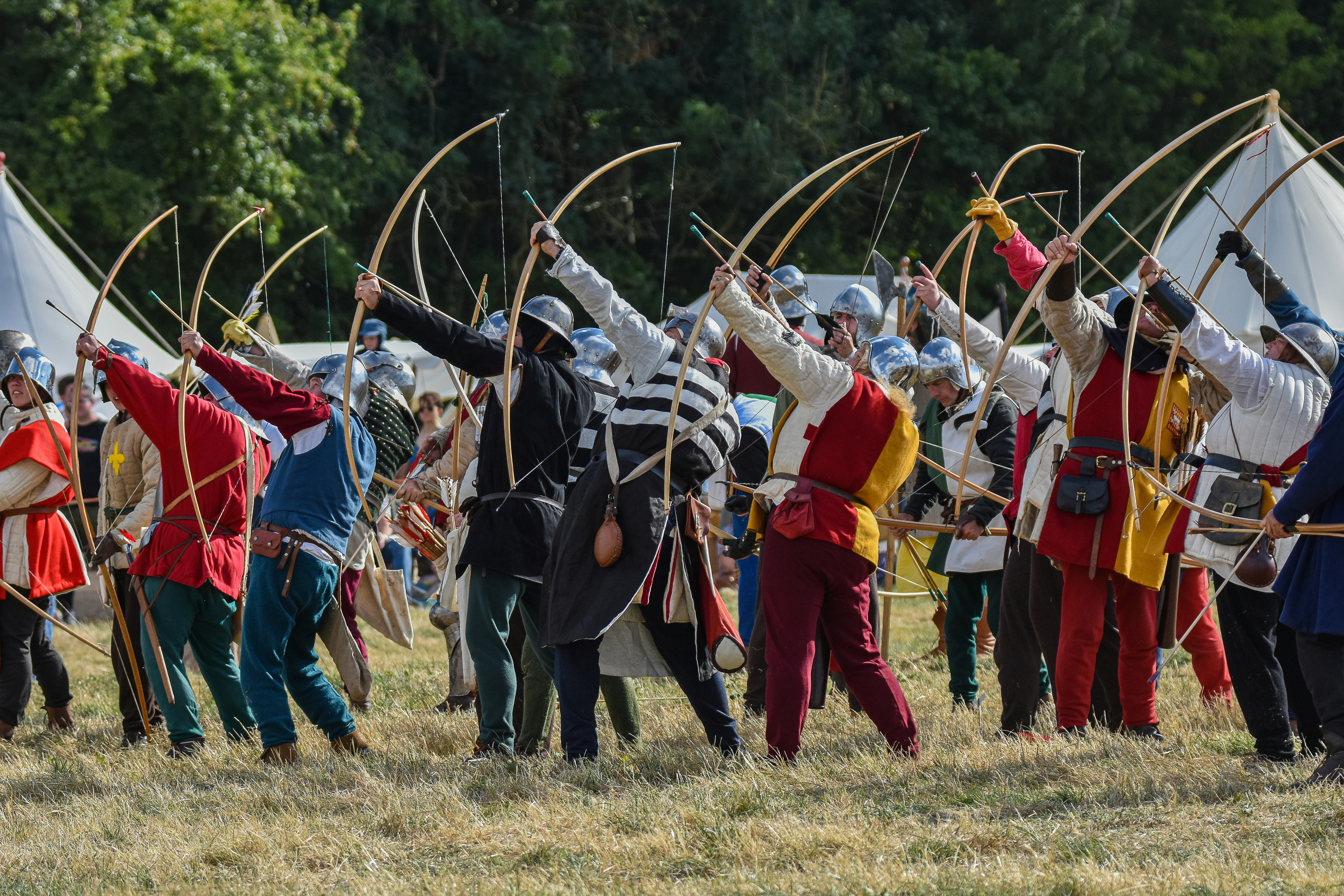 A group of men dressed in medieval clothing holding bows and arrows ...