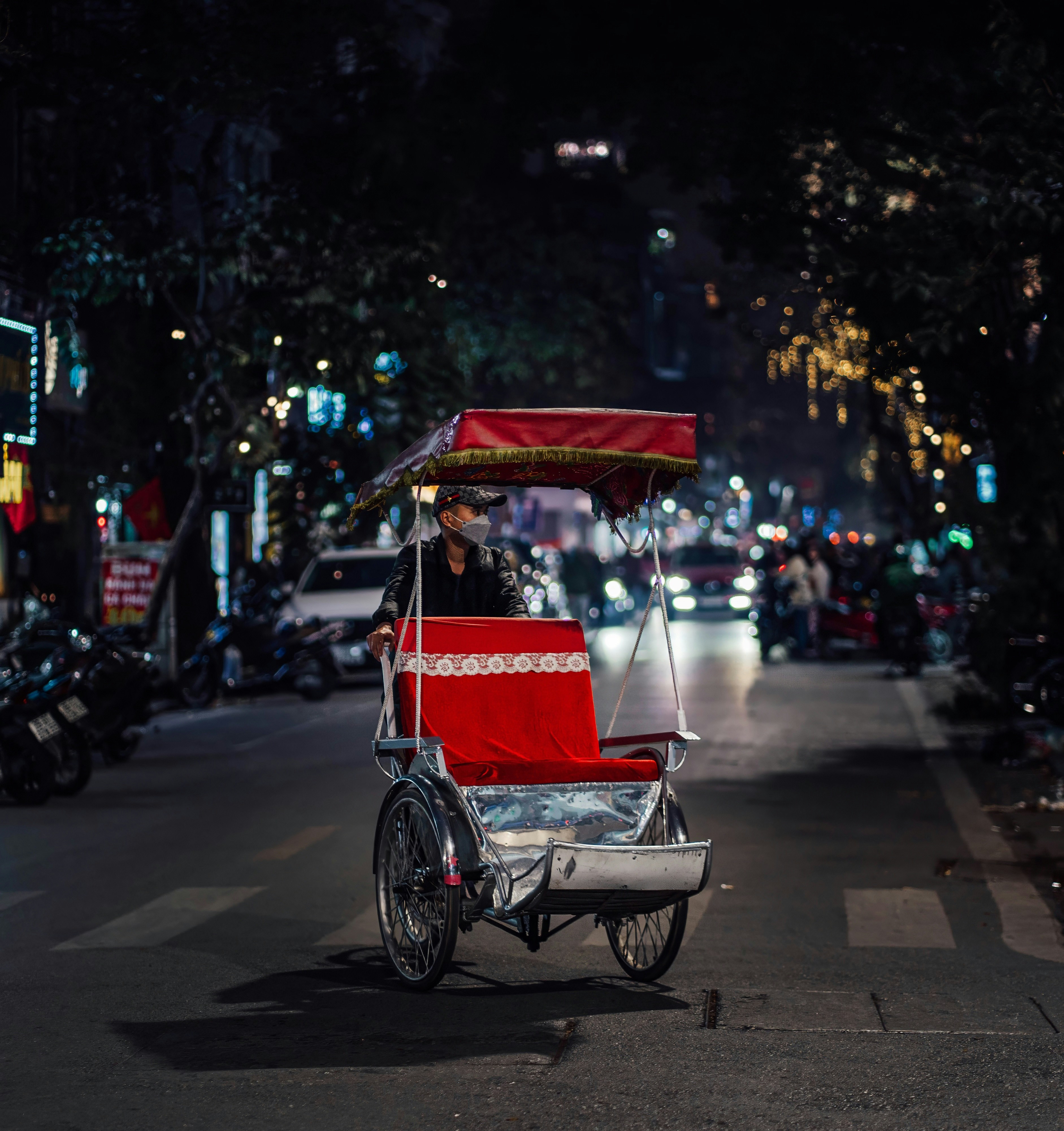 A person riding a rickshaw on a city street at night photo – Free ...