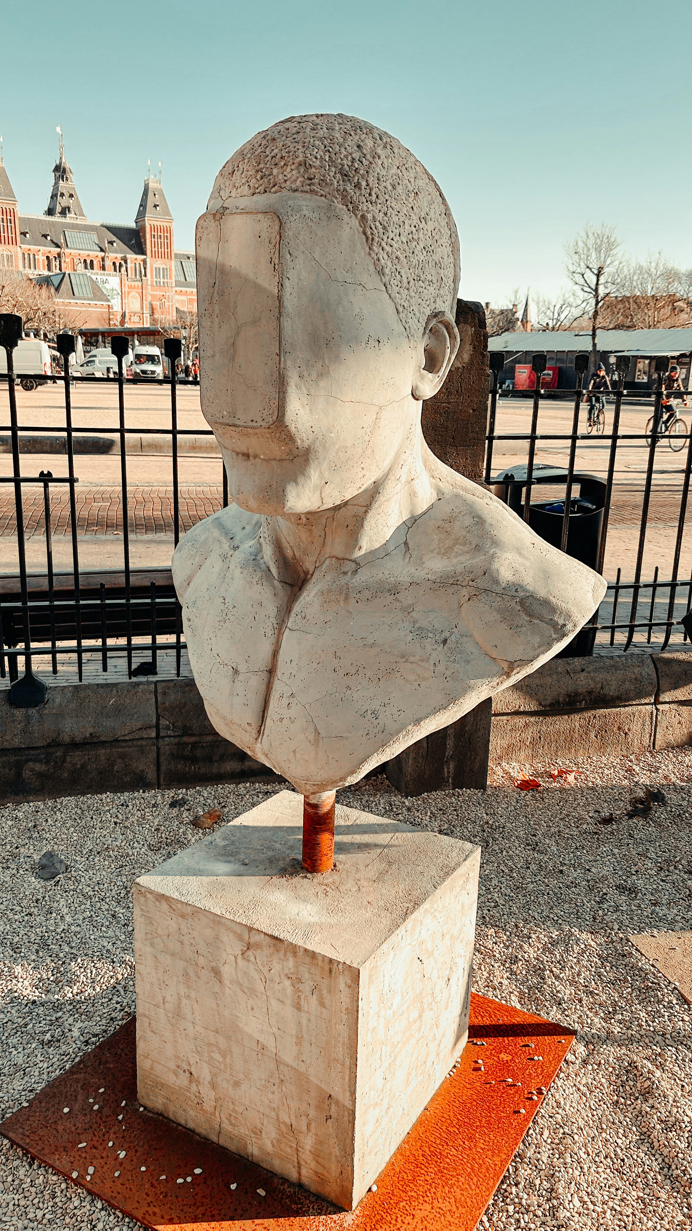 Fragmented Portrait: A Stone Bust with Block Pedestal in a Sunlit Plaza