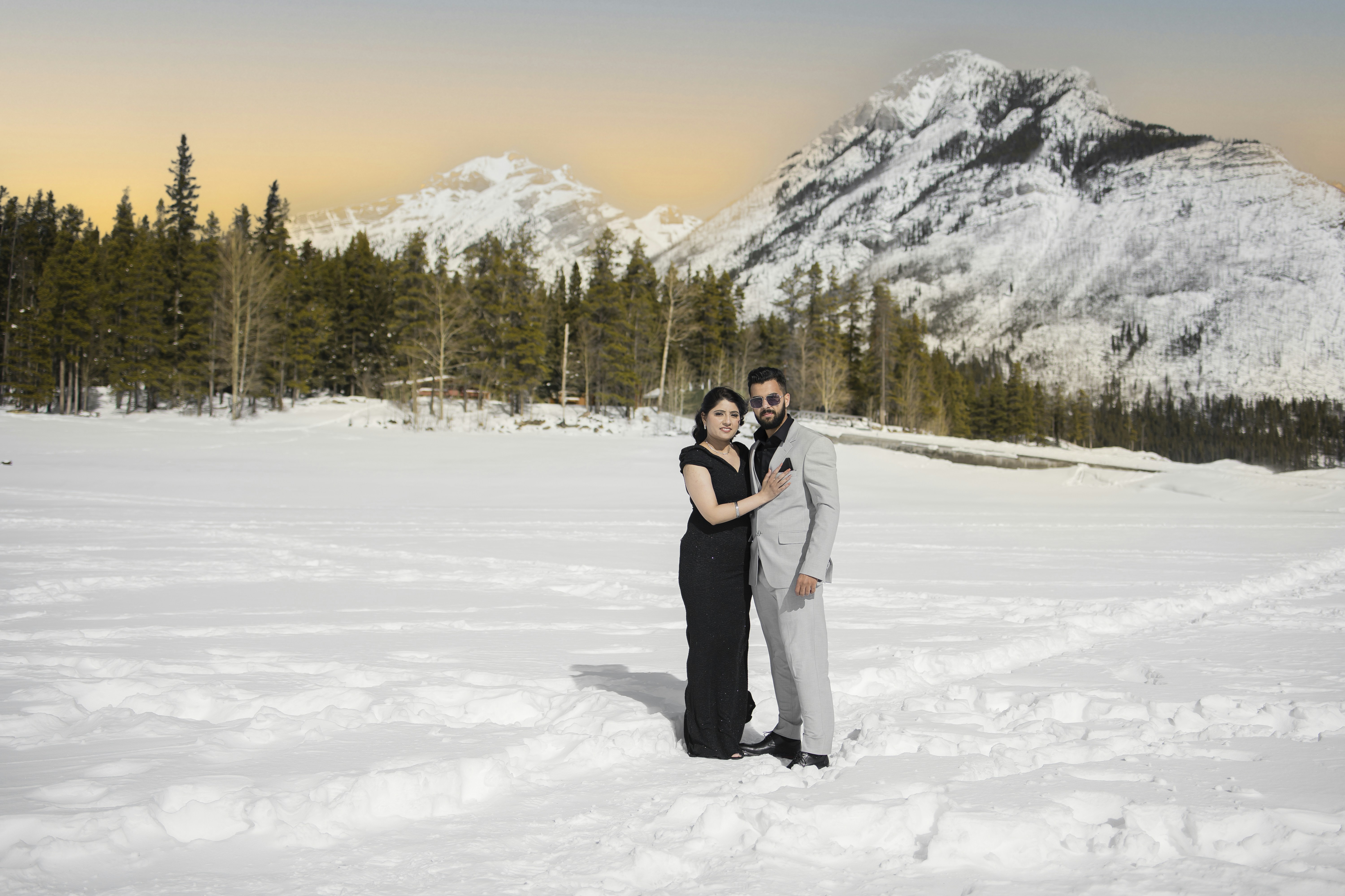 a man and woman standing in the snow in front of a mountain
