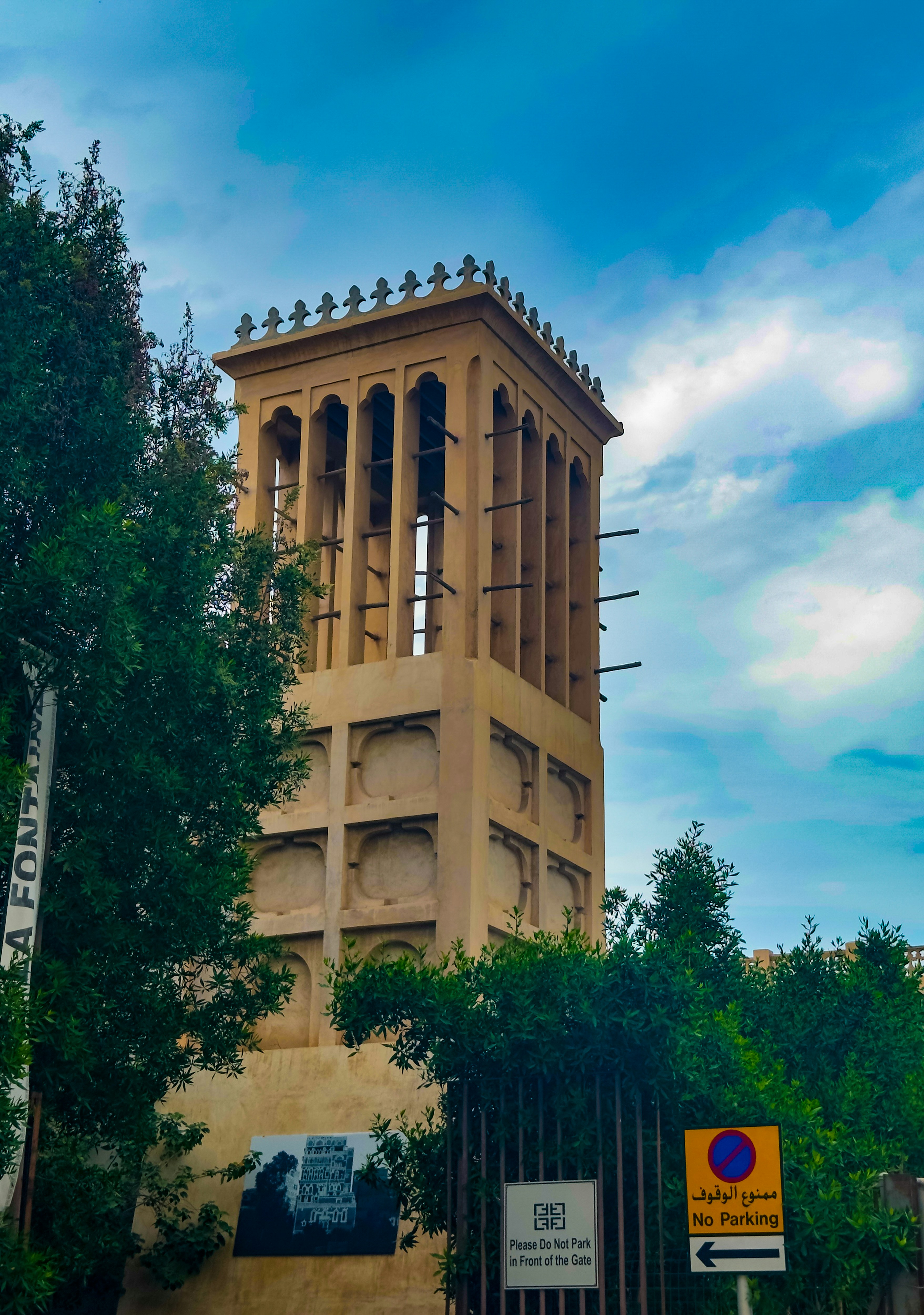 Beige Bell Tower Framed by Foliage Under a Cobalt Sky