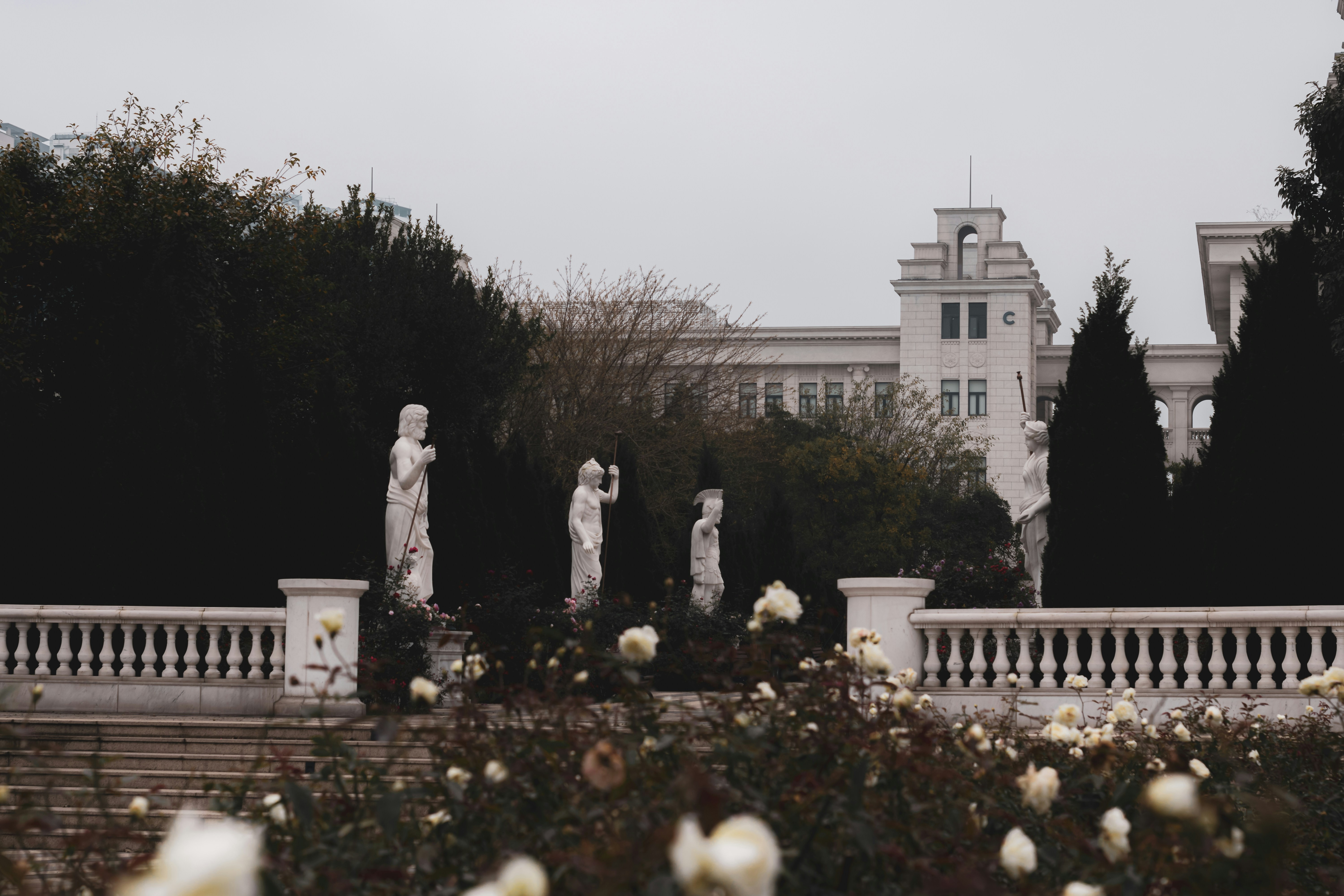 Stone Guardians on a Rose-Covered Terrace Against a Pale Sky