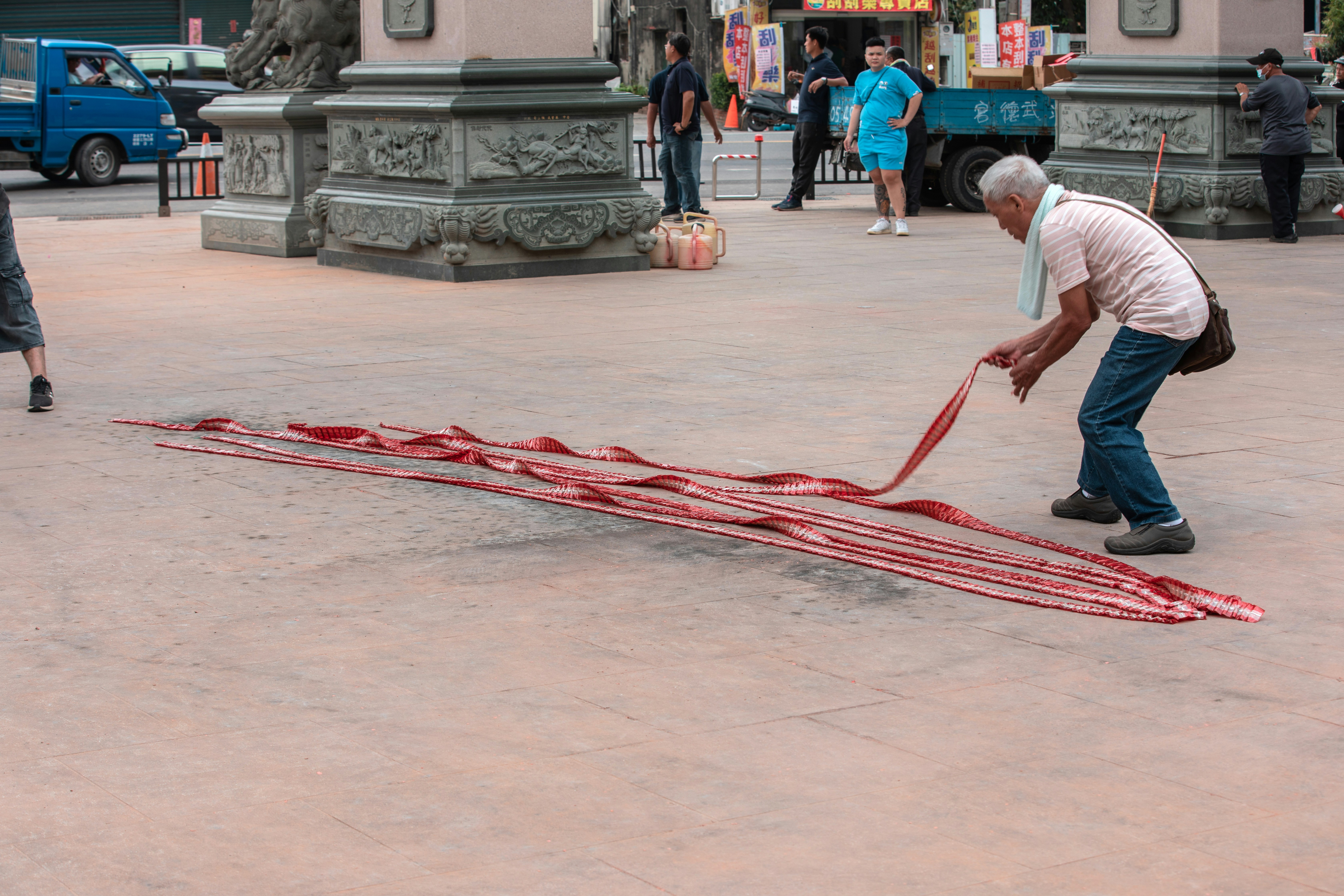 Red Silk Lines: A Street Vendor's Floor Quilt Unfolds at a Public Square