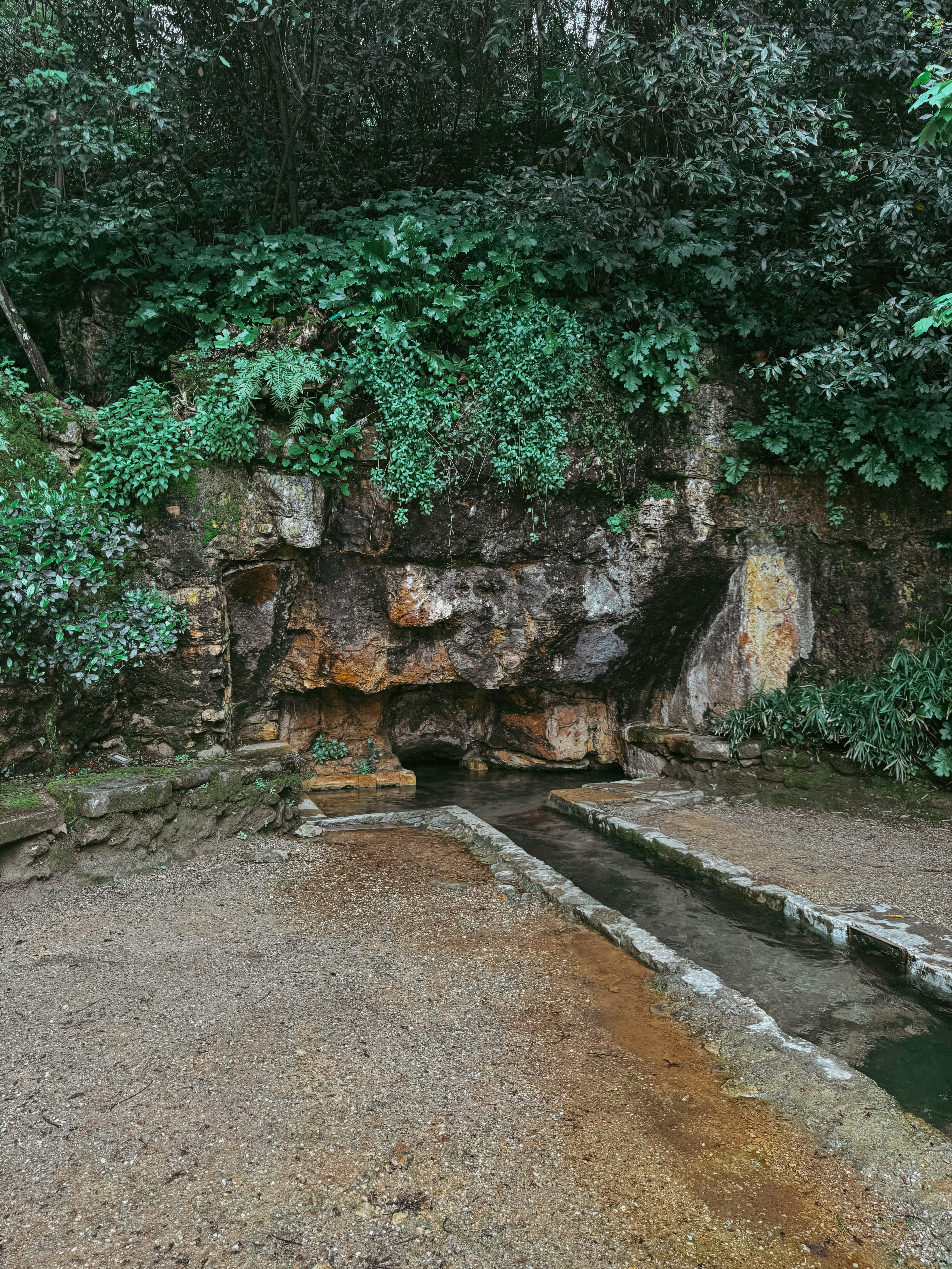 Hidden Cave Nook Framed by Mossy Cliff and Aged Water Channel