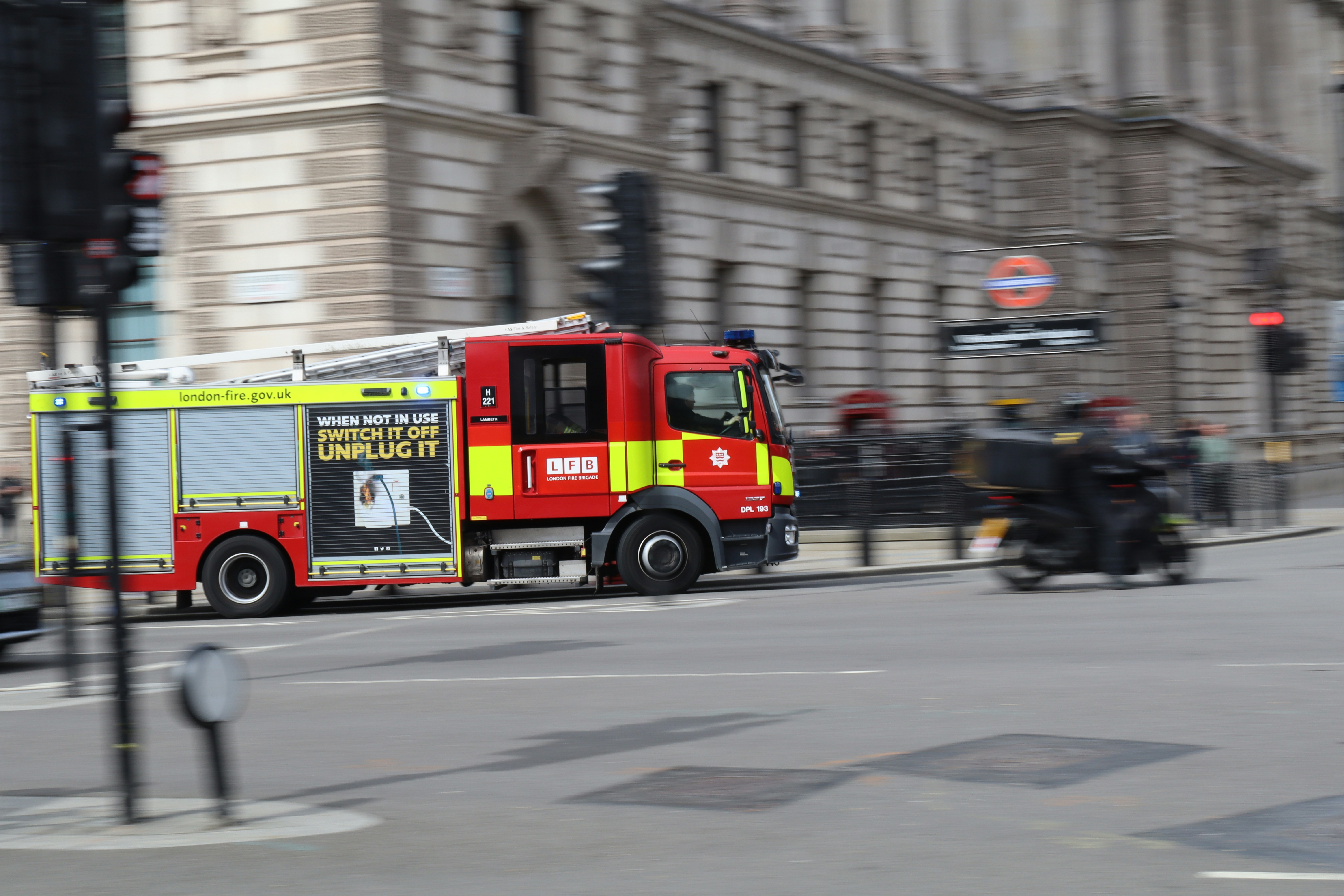 A red and yellow fire truck driving down a street photo – Free London ...