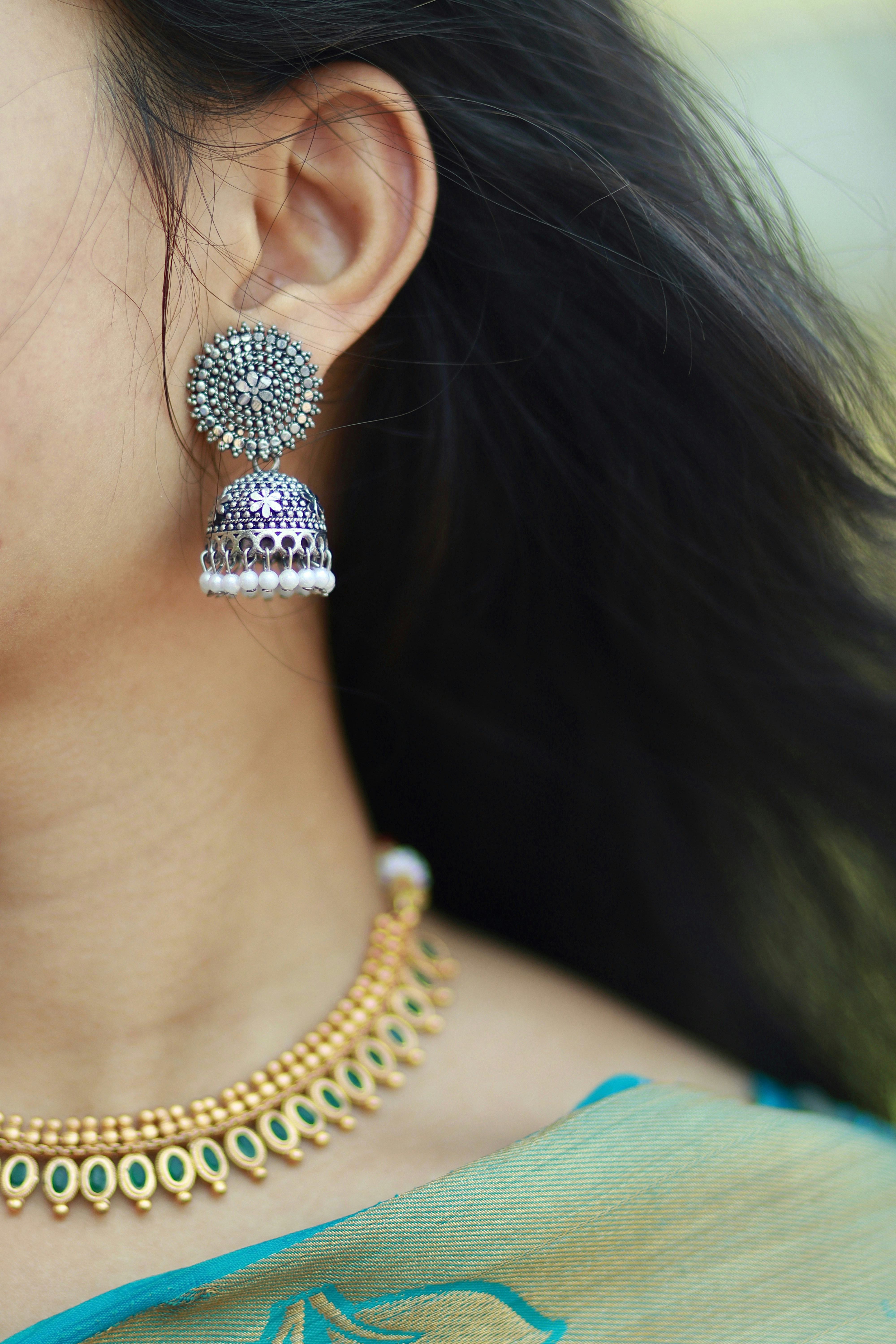 Silver Orbit and Pearl Jhumka: Close-Up of Intricate Jewelry Against Turquoise Silk