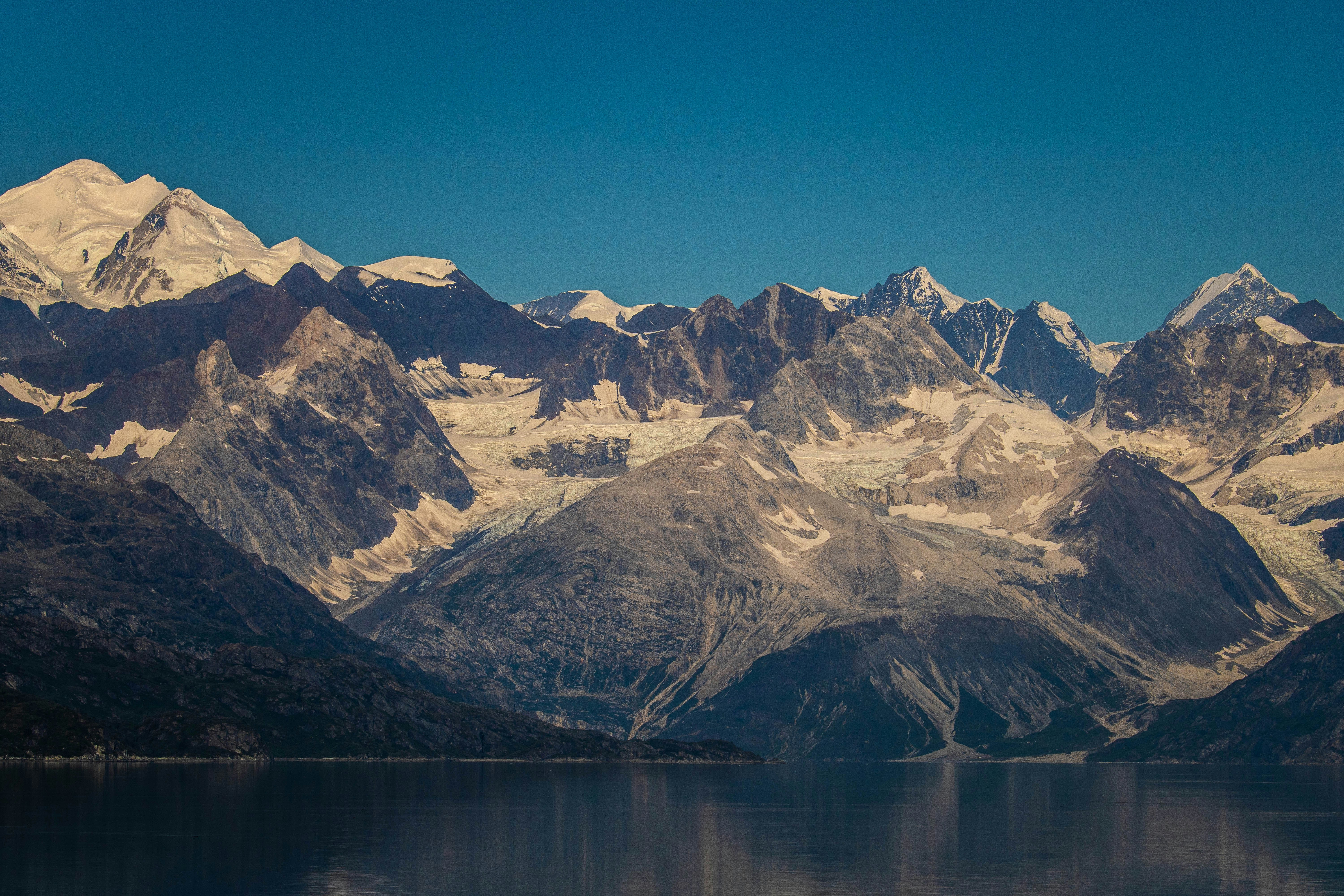 A mountain range with a body of water in front of it photo – Free ...
