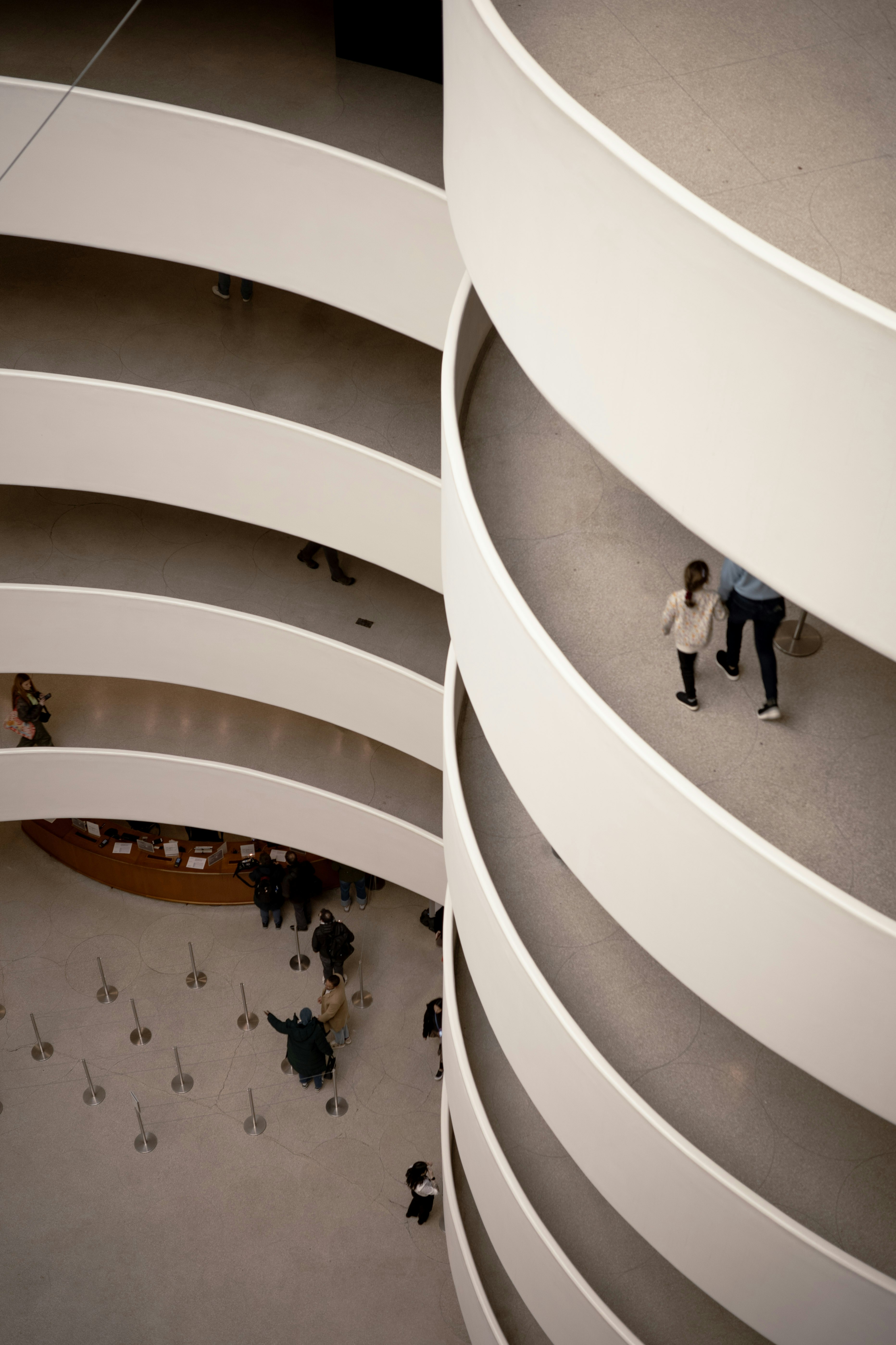 Interior view of a spiraling architectural design showcasing visitors moving along the curved pathways. The scene highlights the interplay of space and human activity.