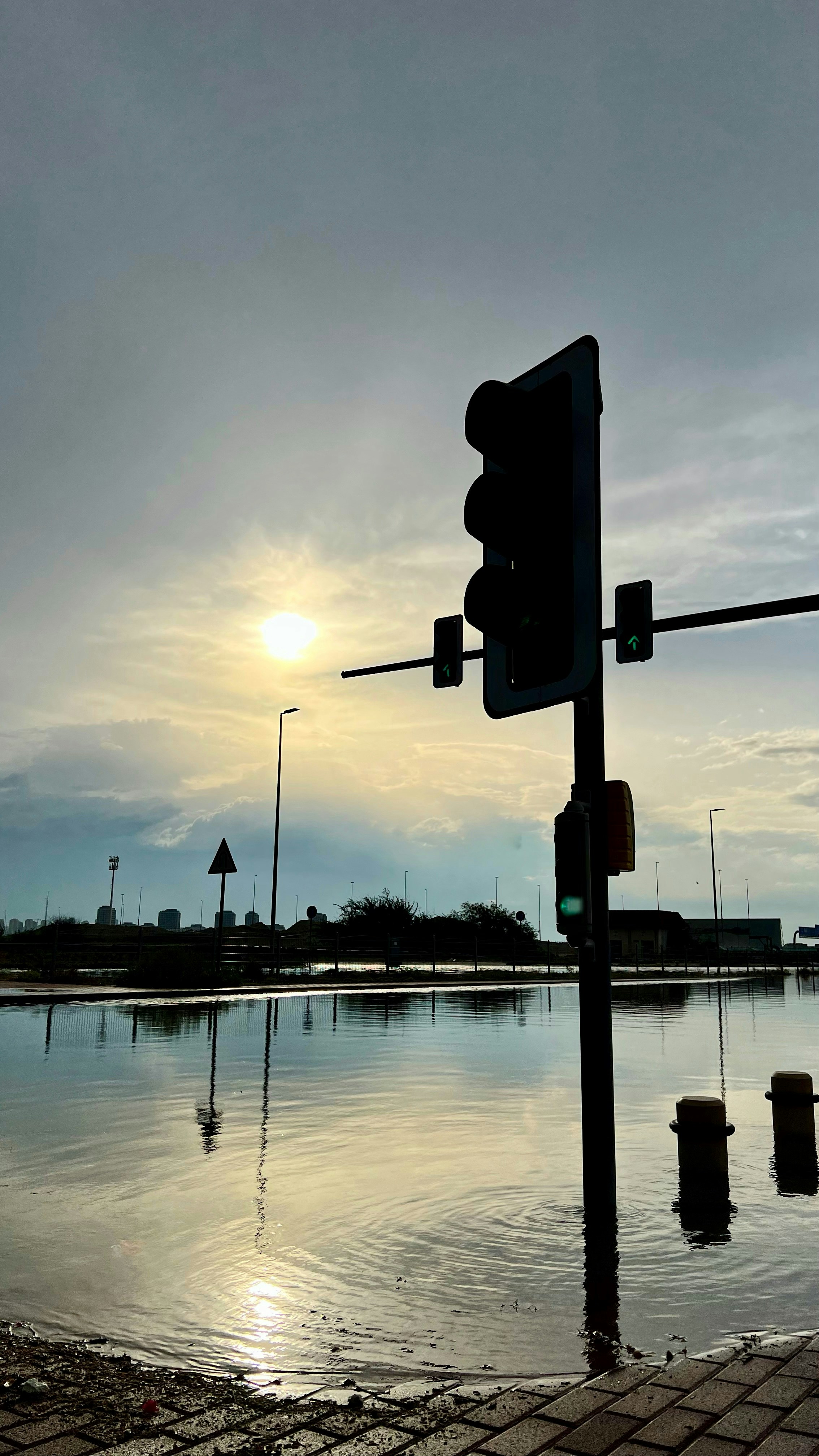 Traffic Signal Silhouette Over a Quiet Waterfront Street at Sunset