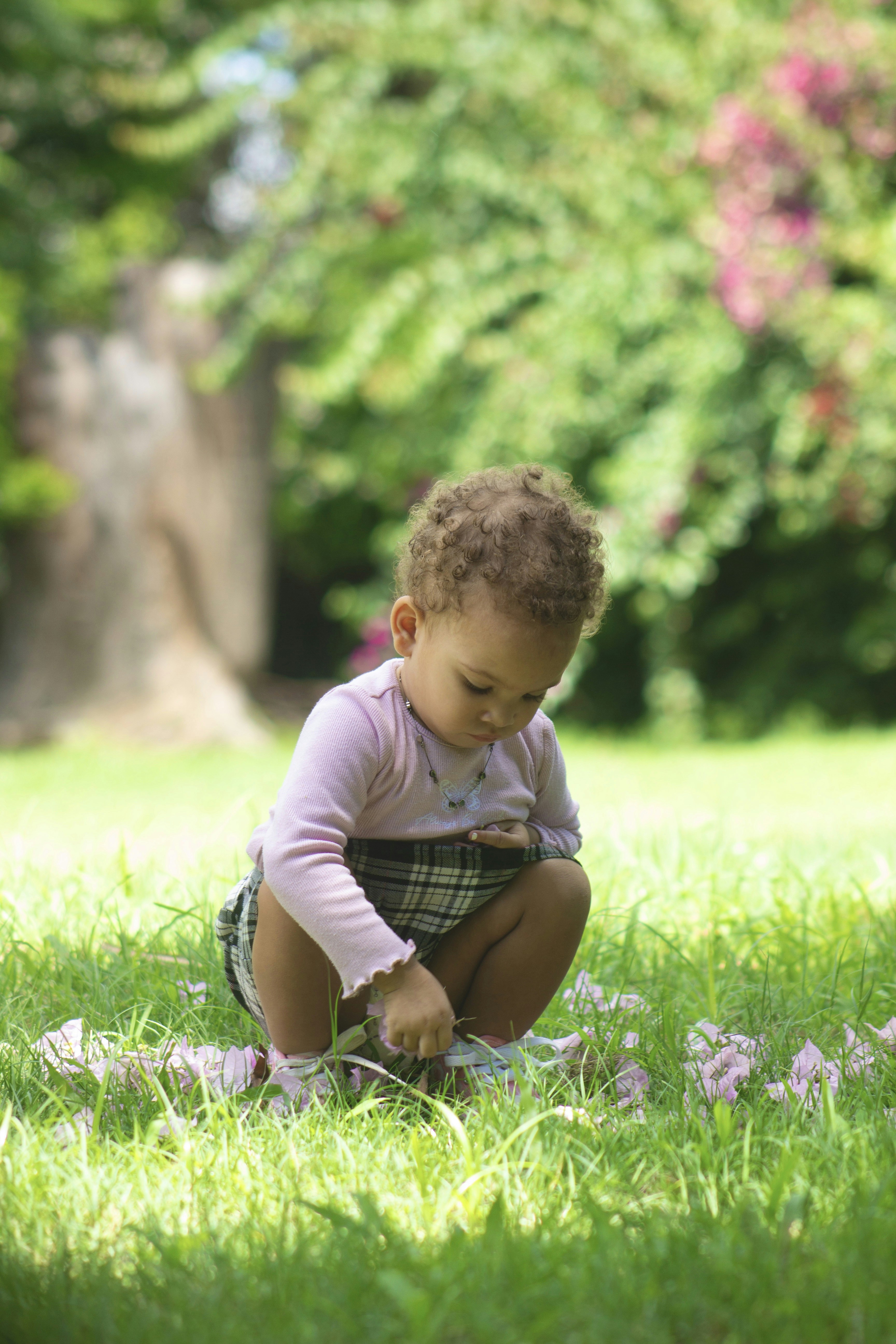 A small child kneeling down in the grass photo – Free Grass Image on ...