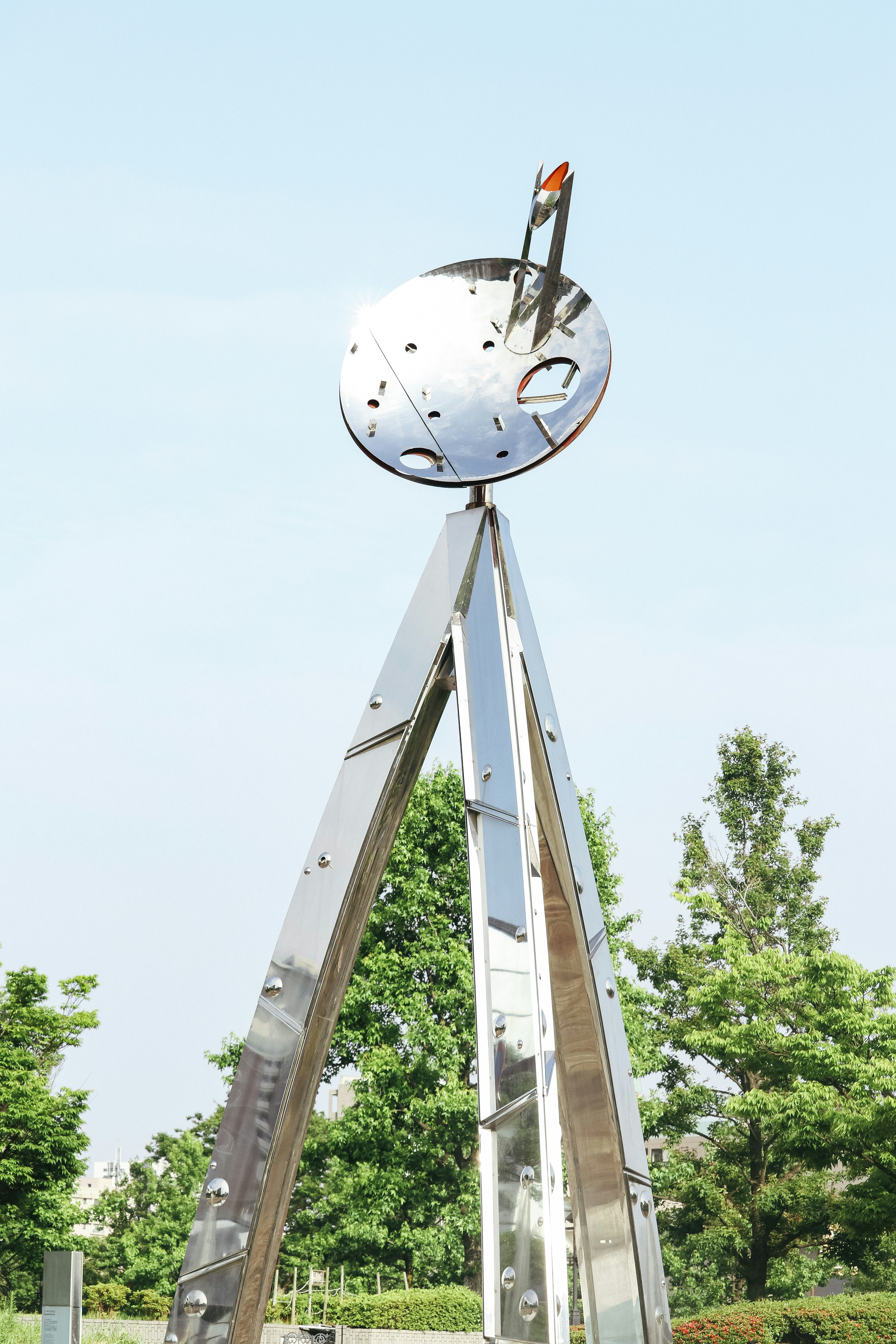 Luminous Disk on Triangular Steel: A Gleaming Outdoor Sculpture