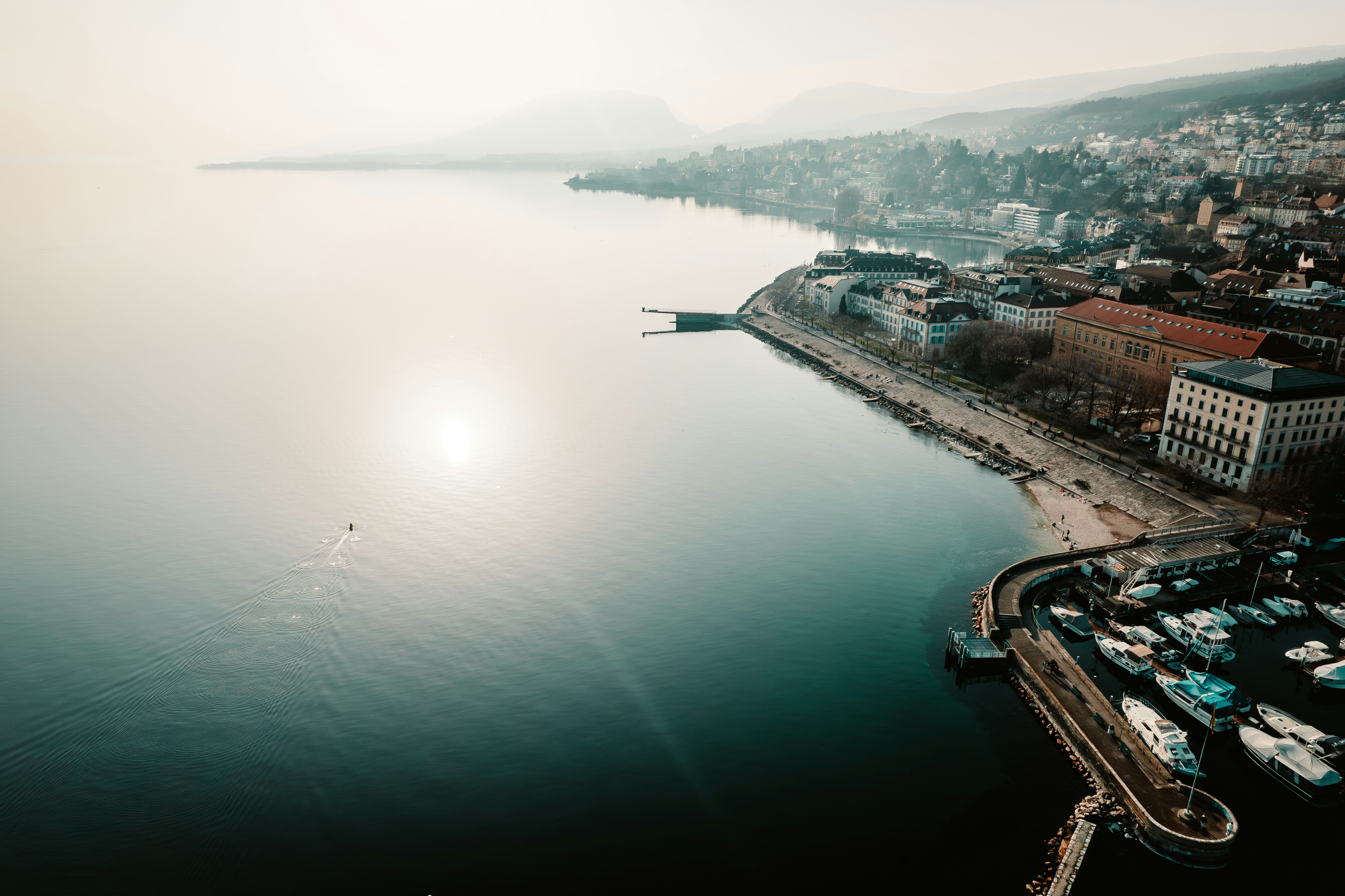 Calm waters reflecting the city skyline under a soft, hazy sky.