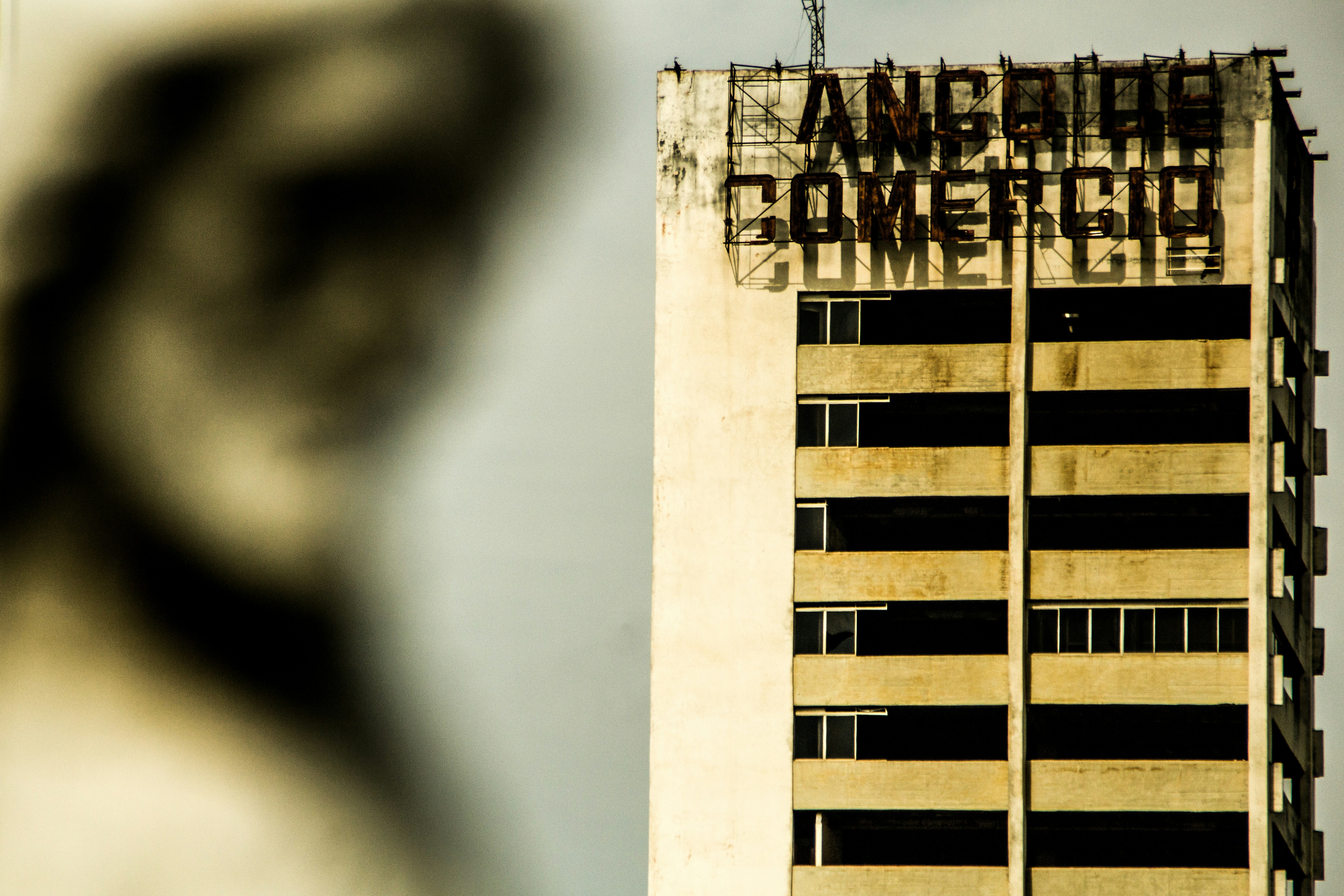 Tall building with faded signage contrasted against a blurred foreground silhouette.