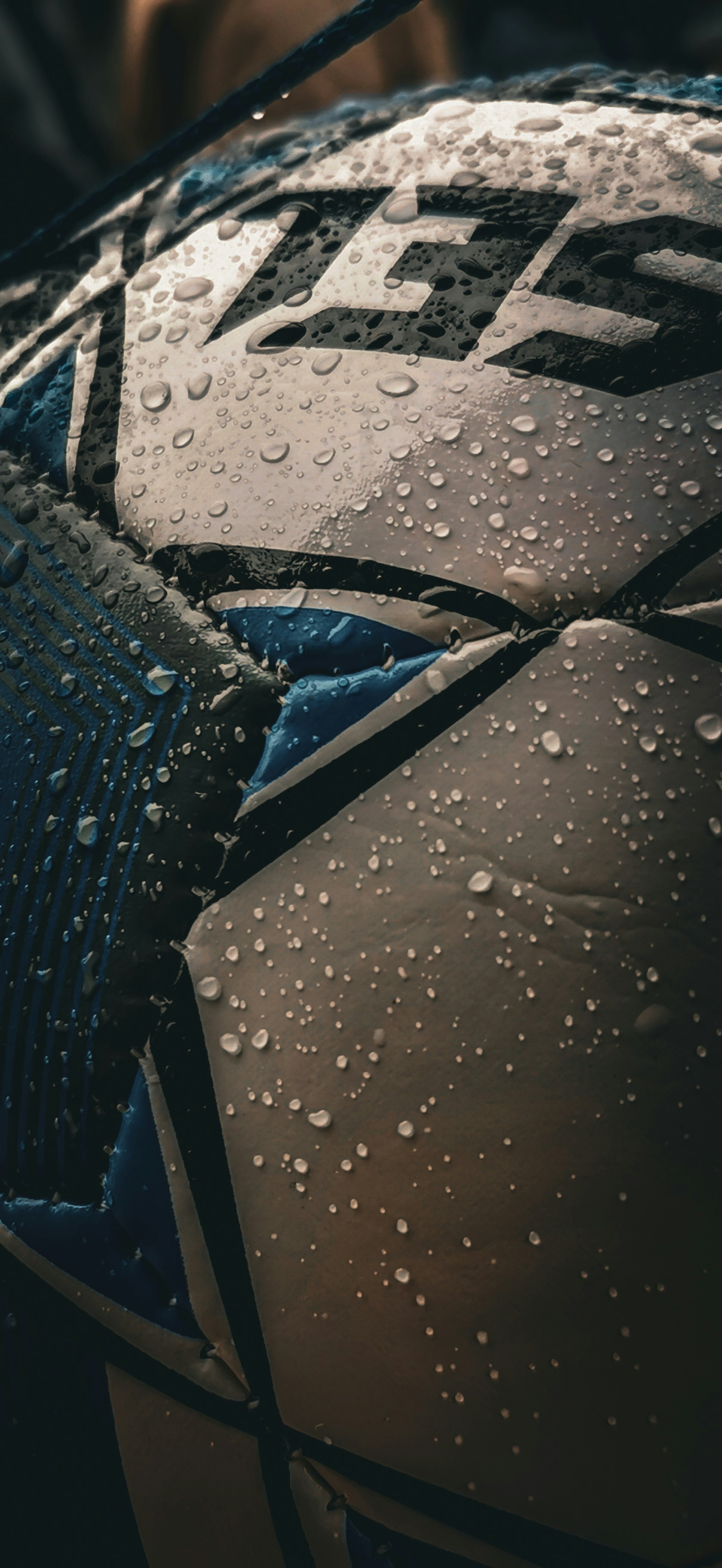 Close-up of a rain-speckled racing helmet displaying a bold logo.