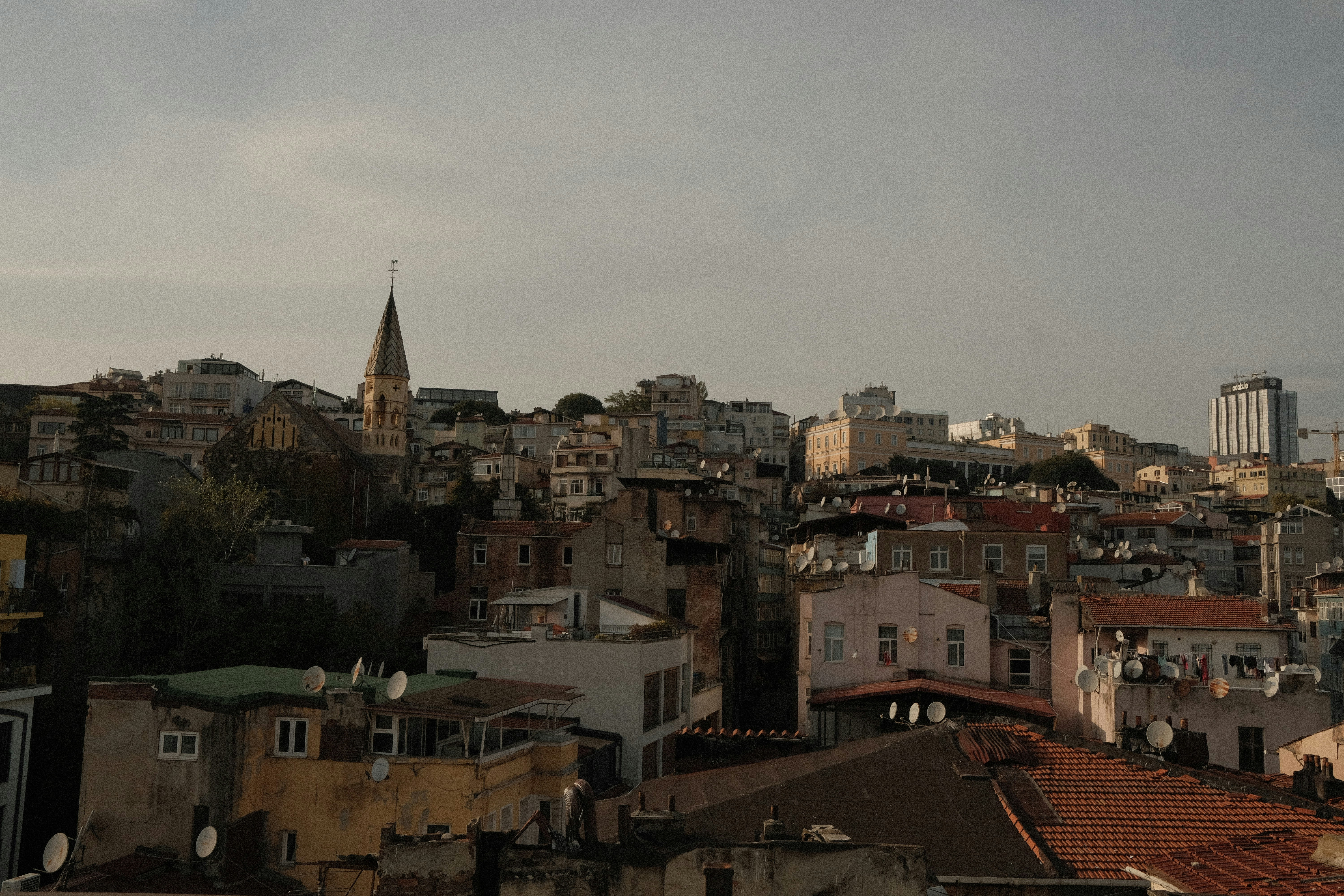 A panoramic view of Istanbul's rooftops, showcasing a blend of historic and modern architecture under a soft evening sky.
