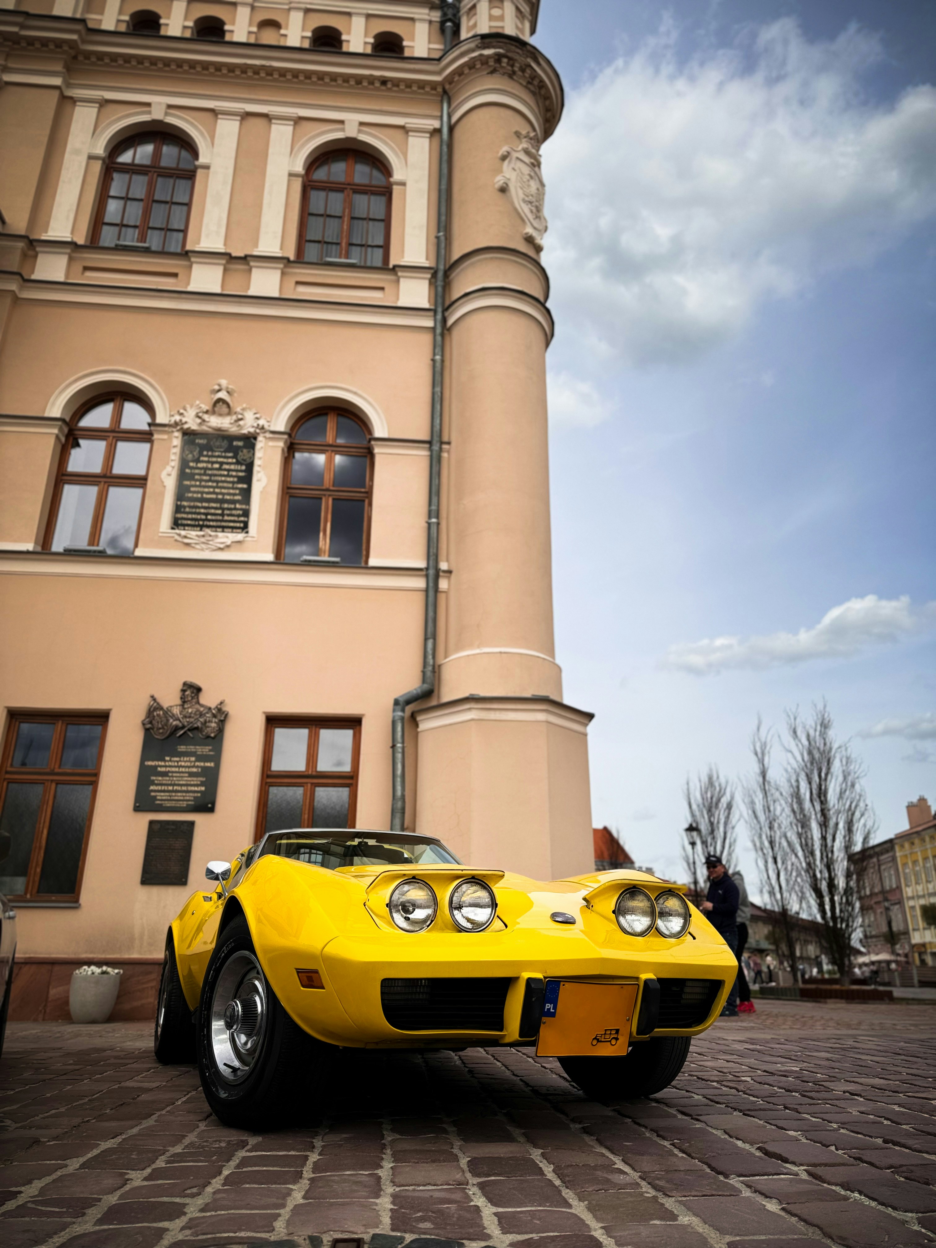 Sunlit Yellow Classic: Vintage Racer Before a Peach-Neoclassical Façade