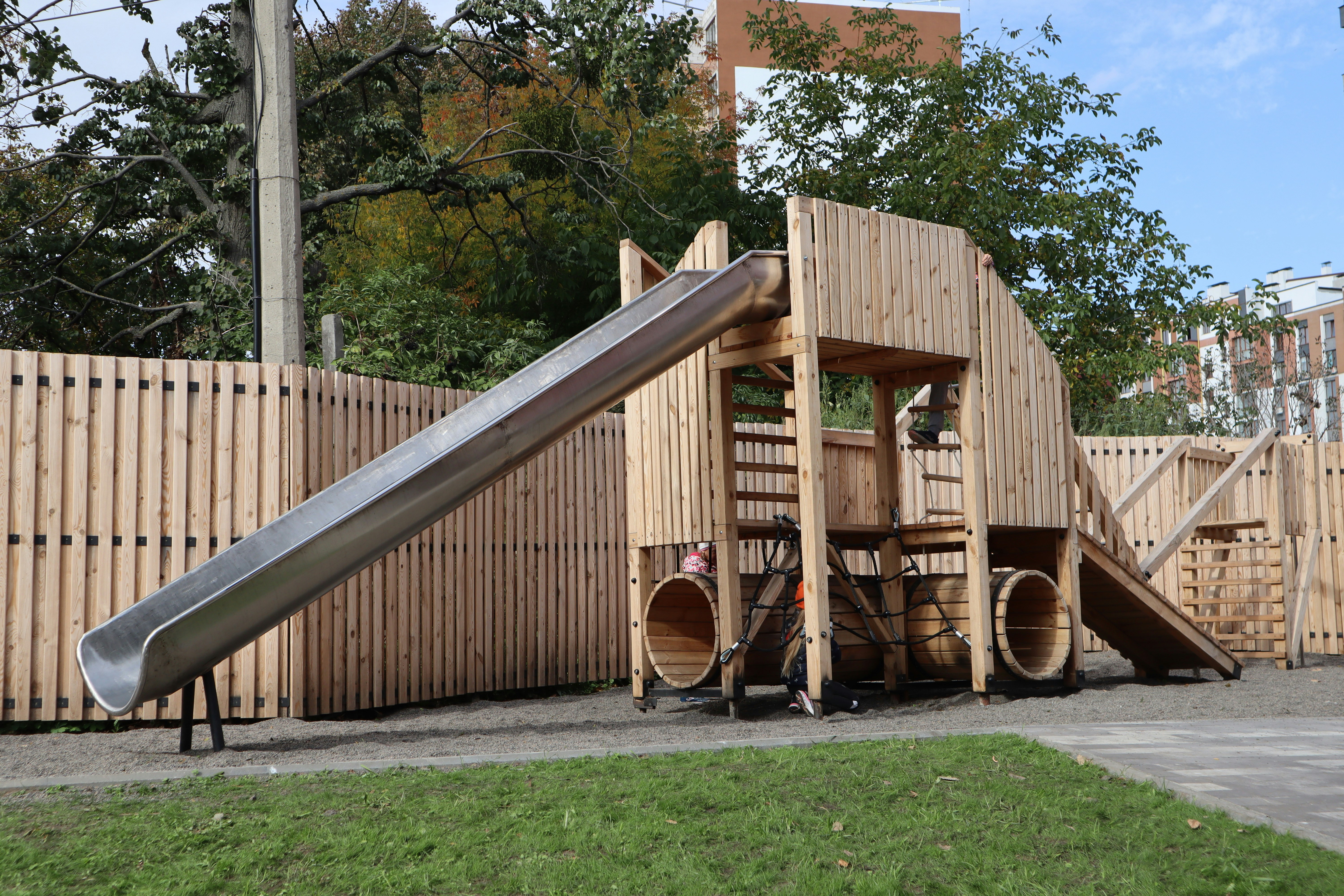 A wooden play structure with a slide in the middle of it photo – Free ...