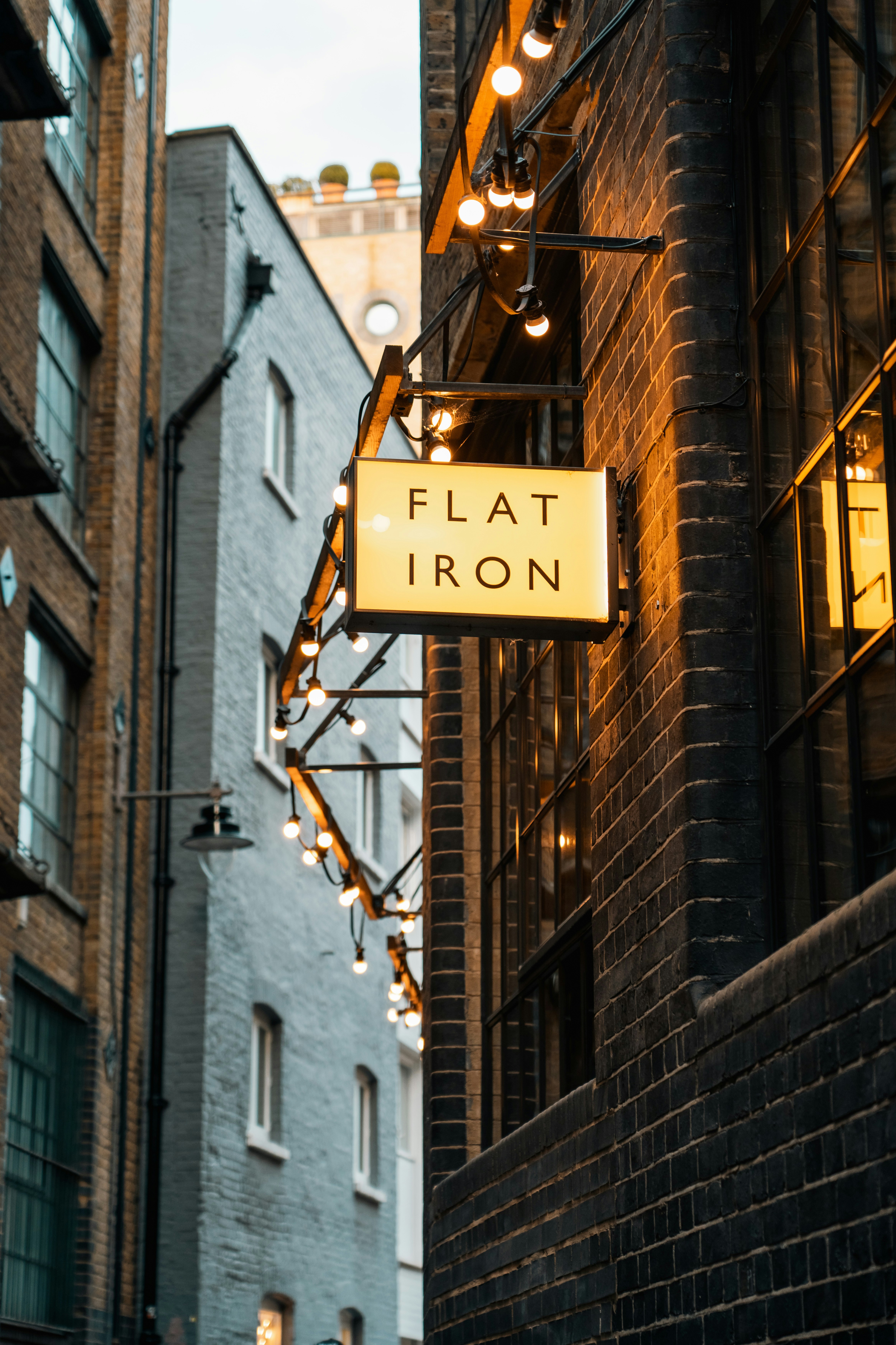 Flat Iron Sign: A Warm Beacon in a Narrow Brick Alley