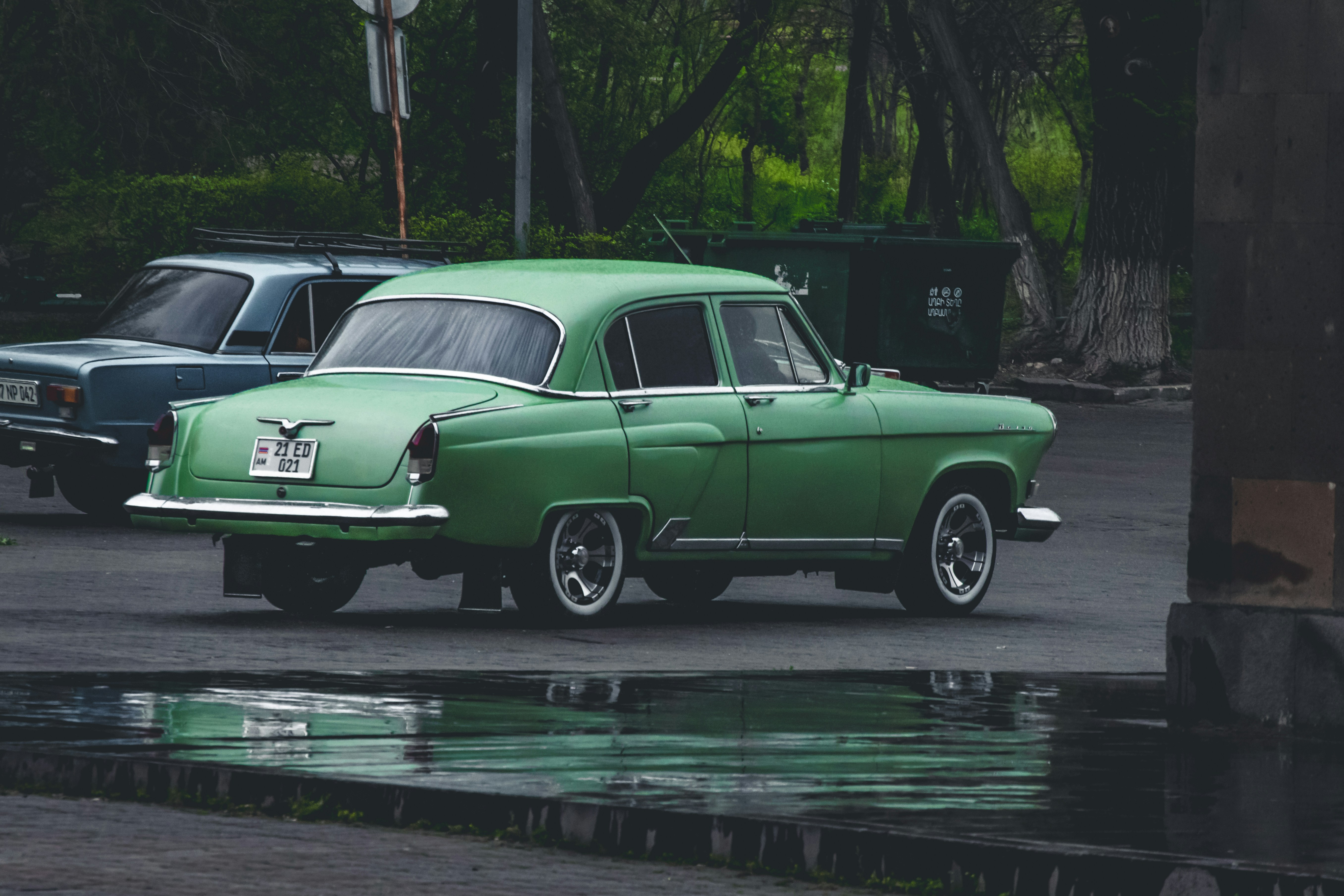 Emerald Classic in the Rain: A 1950s Sedan Resting by Wet Pavement