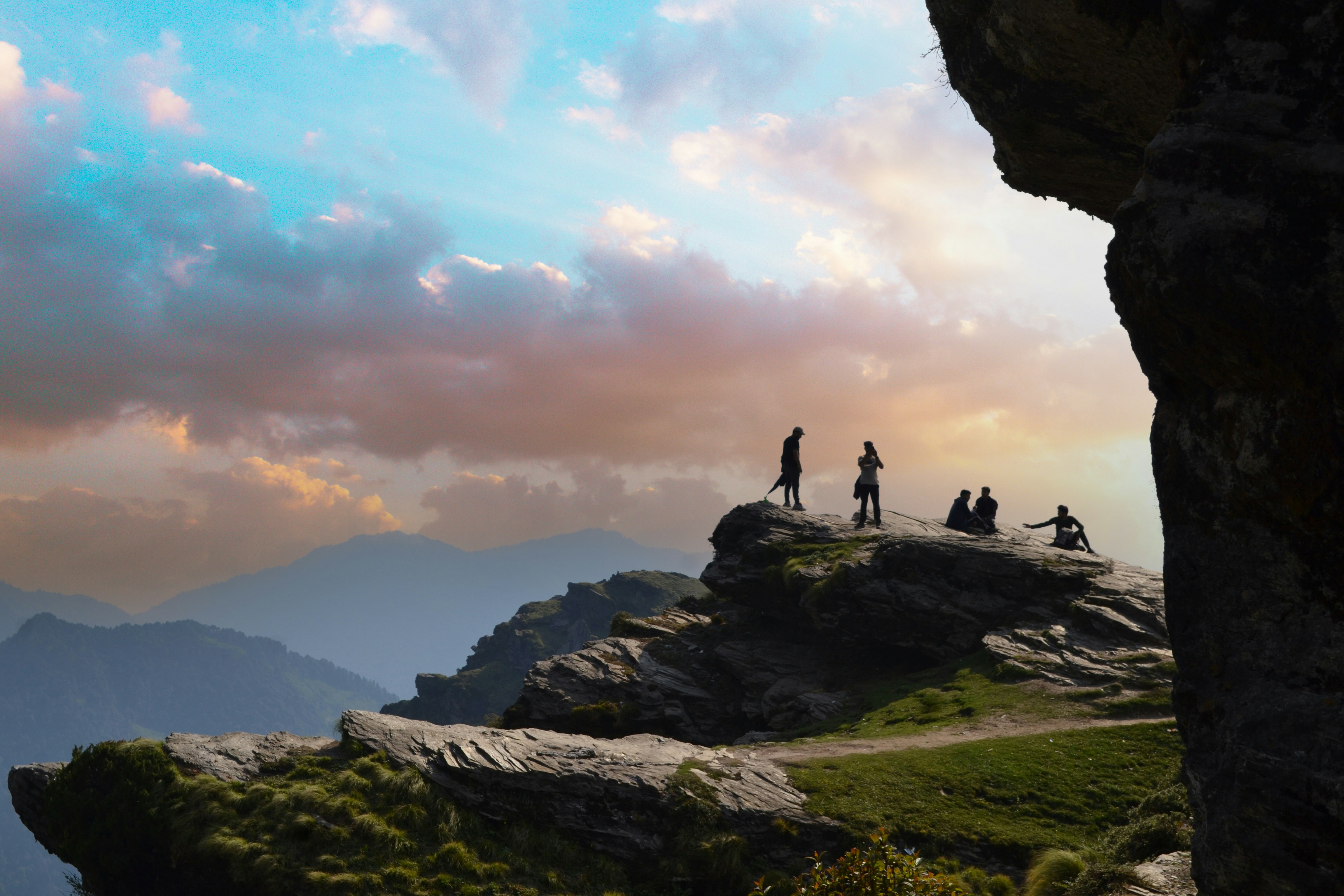 Cliffside silhouetted hikers on a sunlit ridge