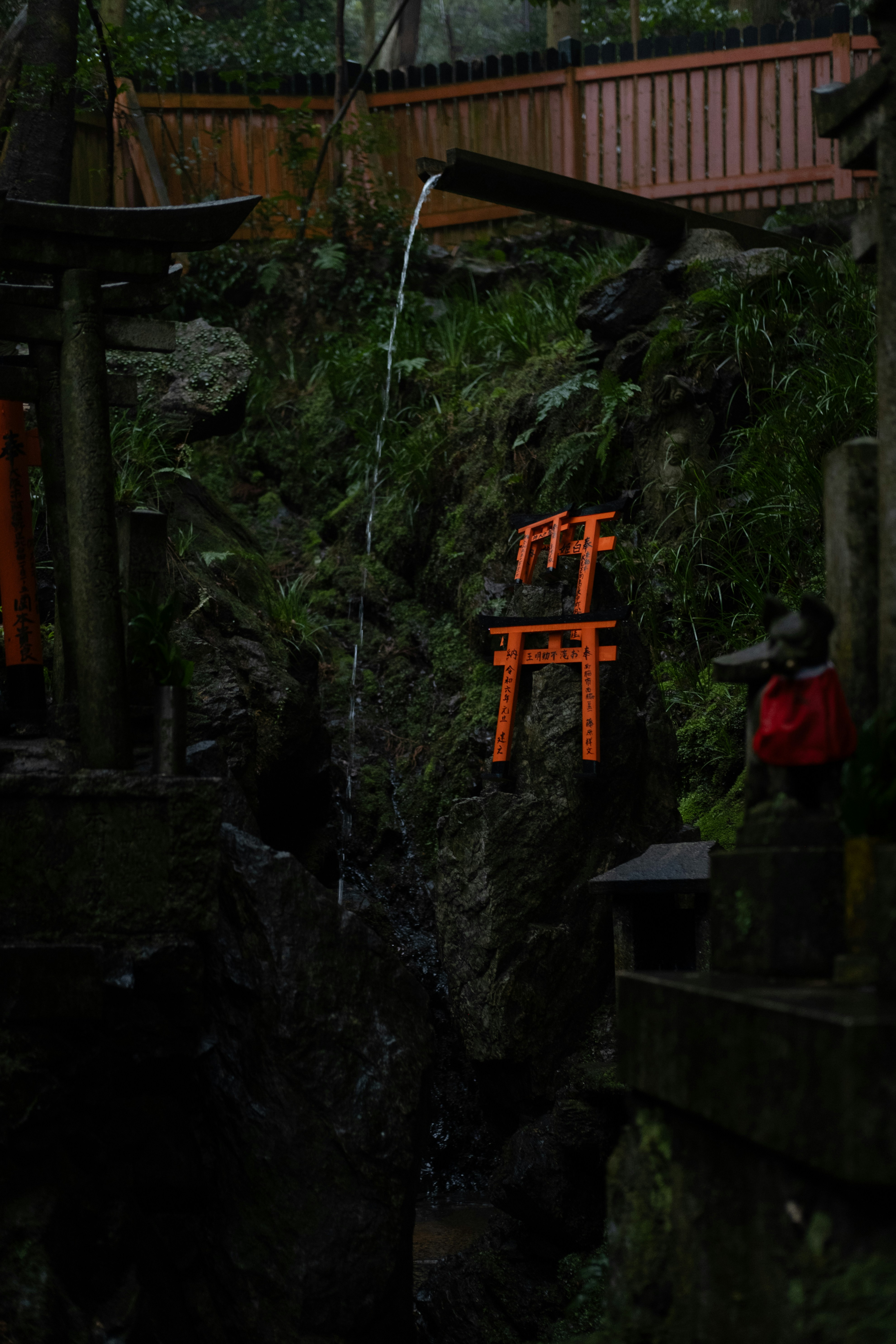 Vermilion Torii Through a Moss-Draped Gorge by a Quiet Waterfall