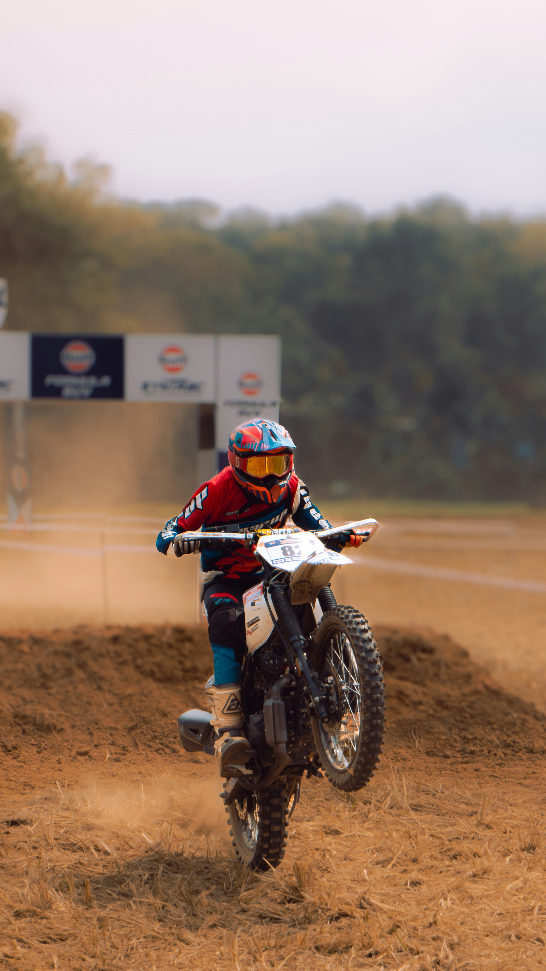 Dust Trail Gambit: Red-Blue Moto Cross Leap Over a Sandy Track