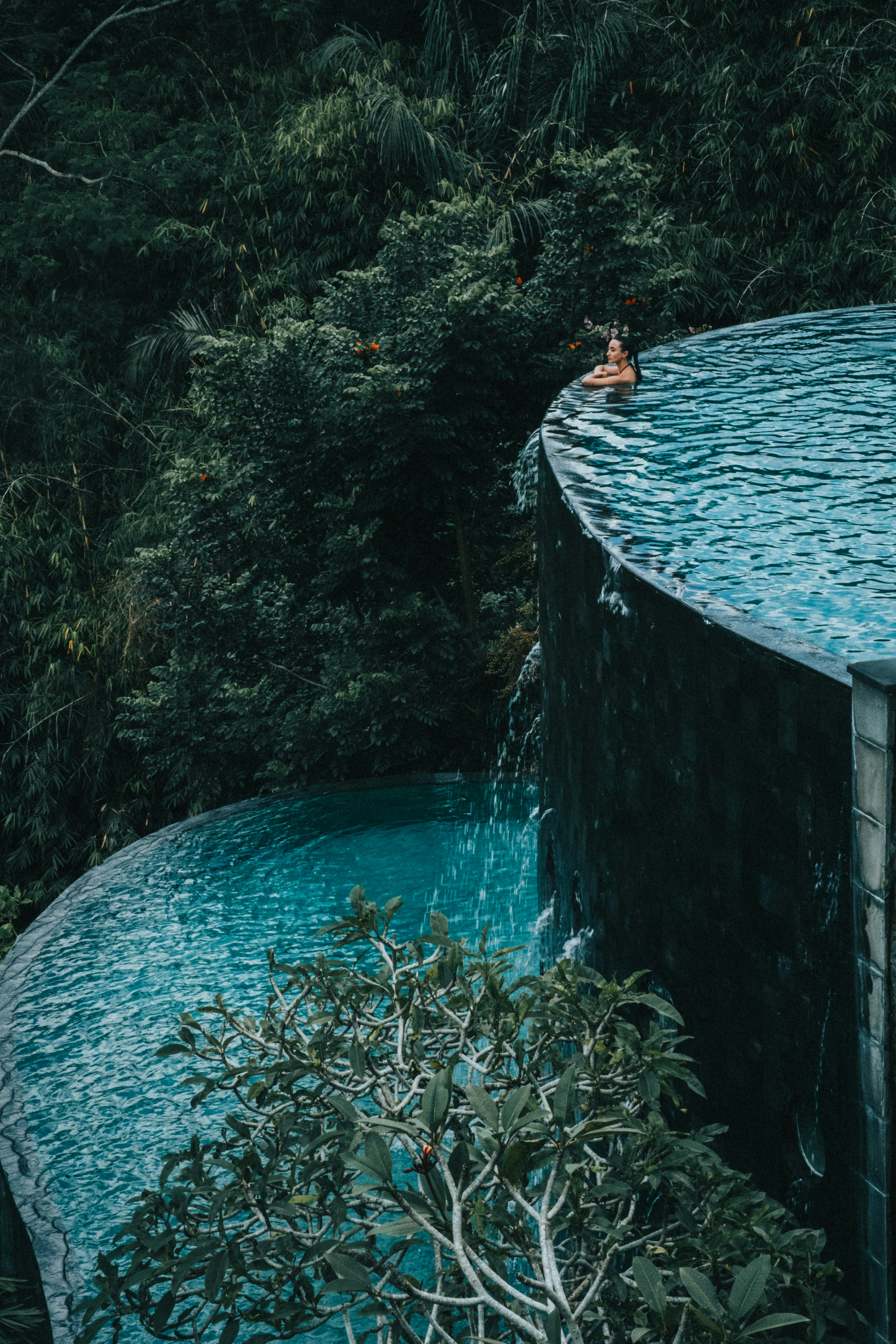 Rim of the Sky: A solitary swimmer at the edge of a turquoise cliffside infinity pool