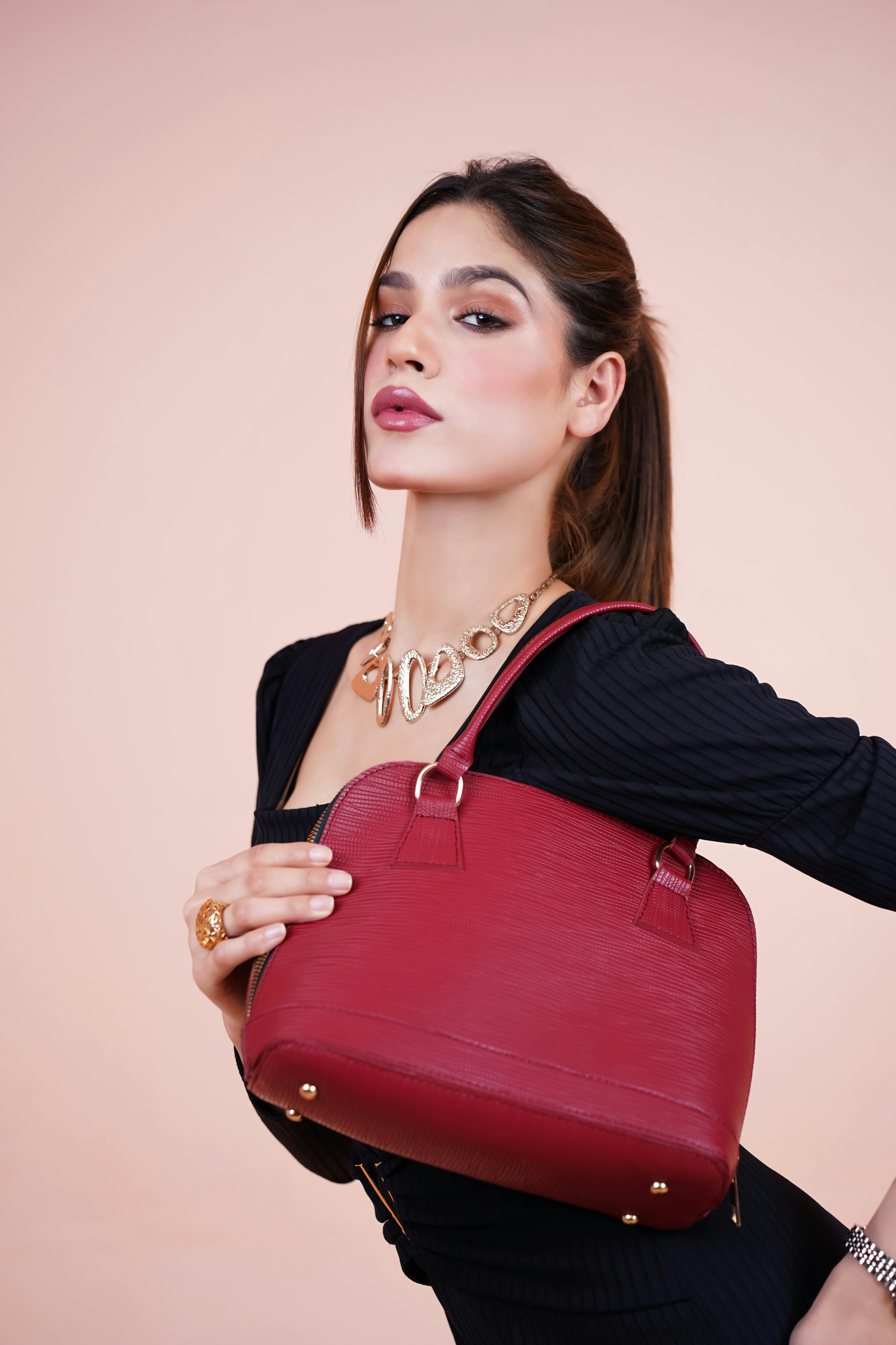 Scarlet Satchel and Poised Gaze: Studio Portrait with Peach Backdrop