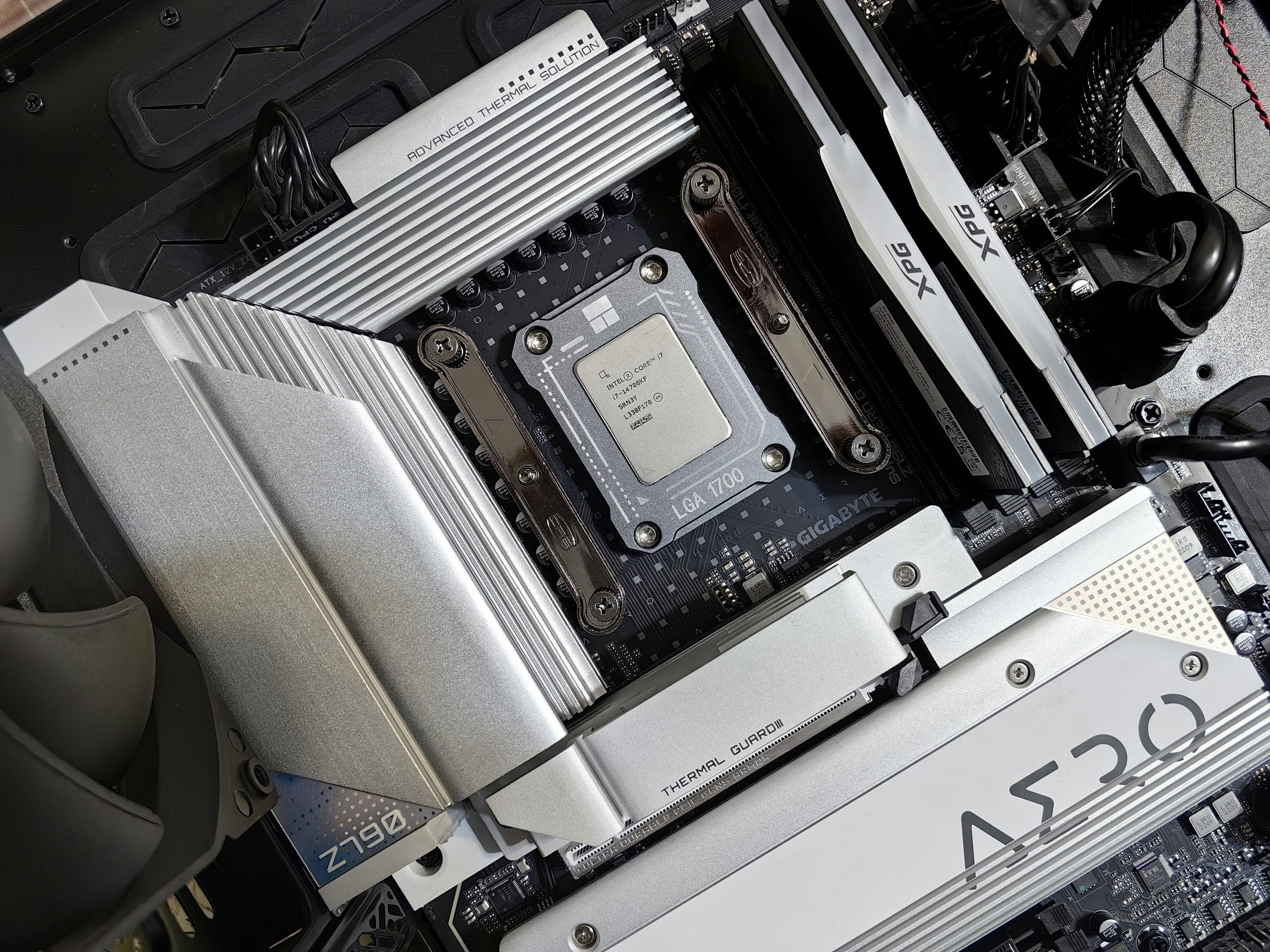 Close-up photograph of a motherboard highlighting the LGA 1700 CPU socket, chrome heatsinks, and XPG RAM modules.